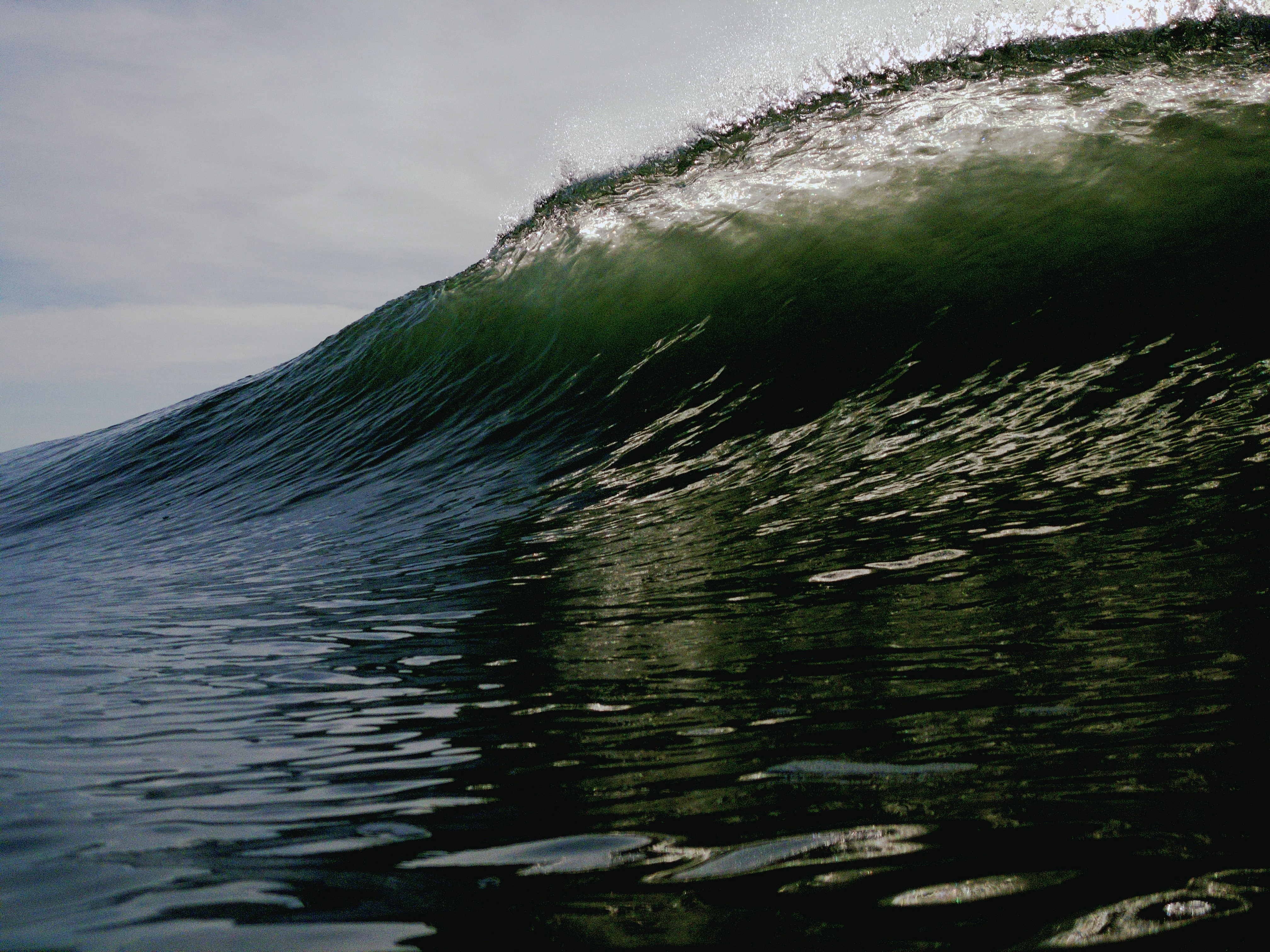 Emerald Barrel: Sunlit Crest Curling Over a Glassy Sea