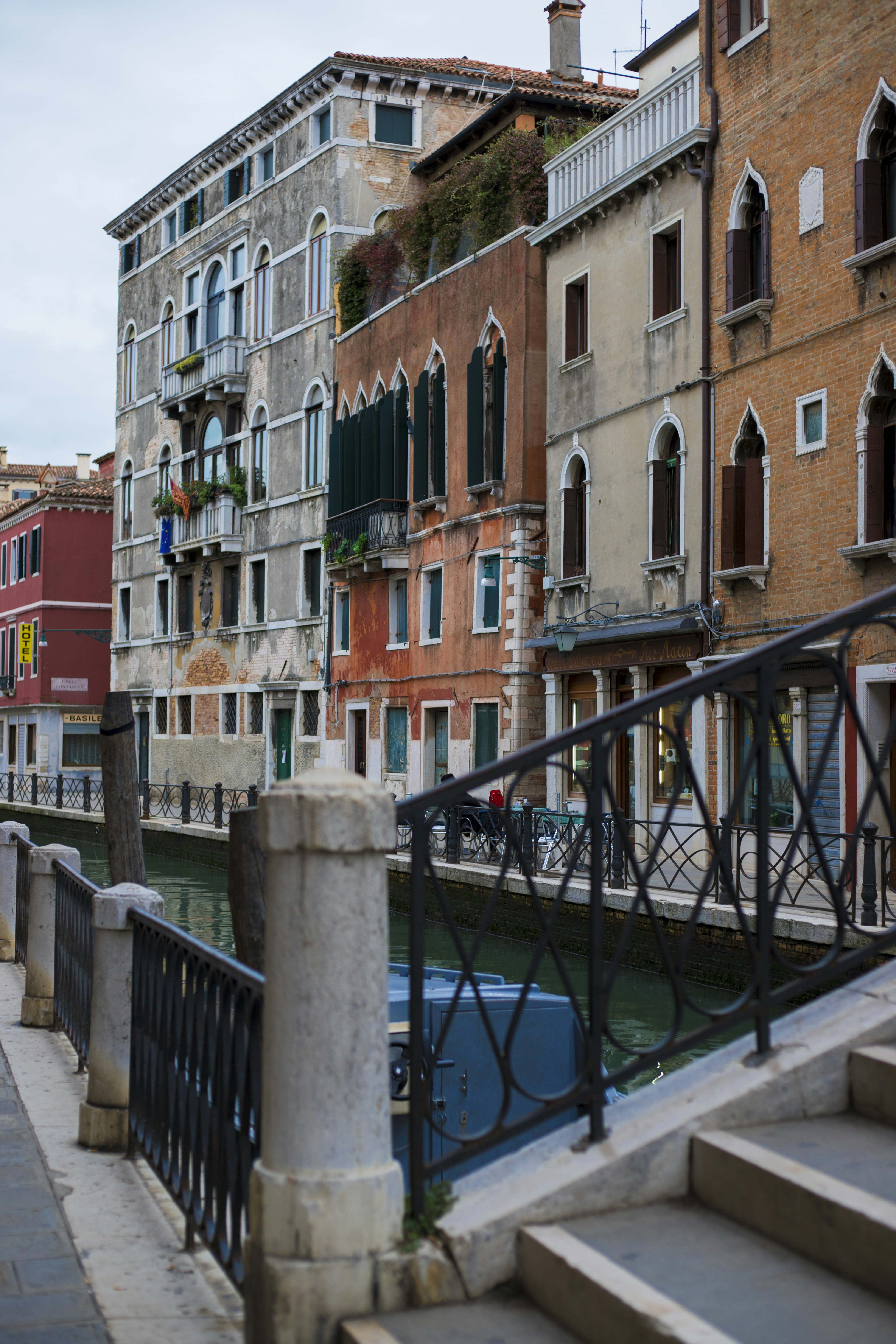 Charming Venetian buildings line a tranquil canal, showcasing intricate architecture and vibrant colors. A serene atmosphere invites exploration.