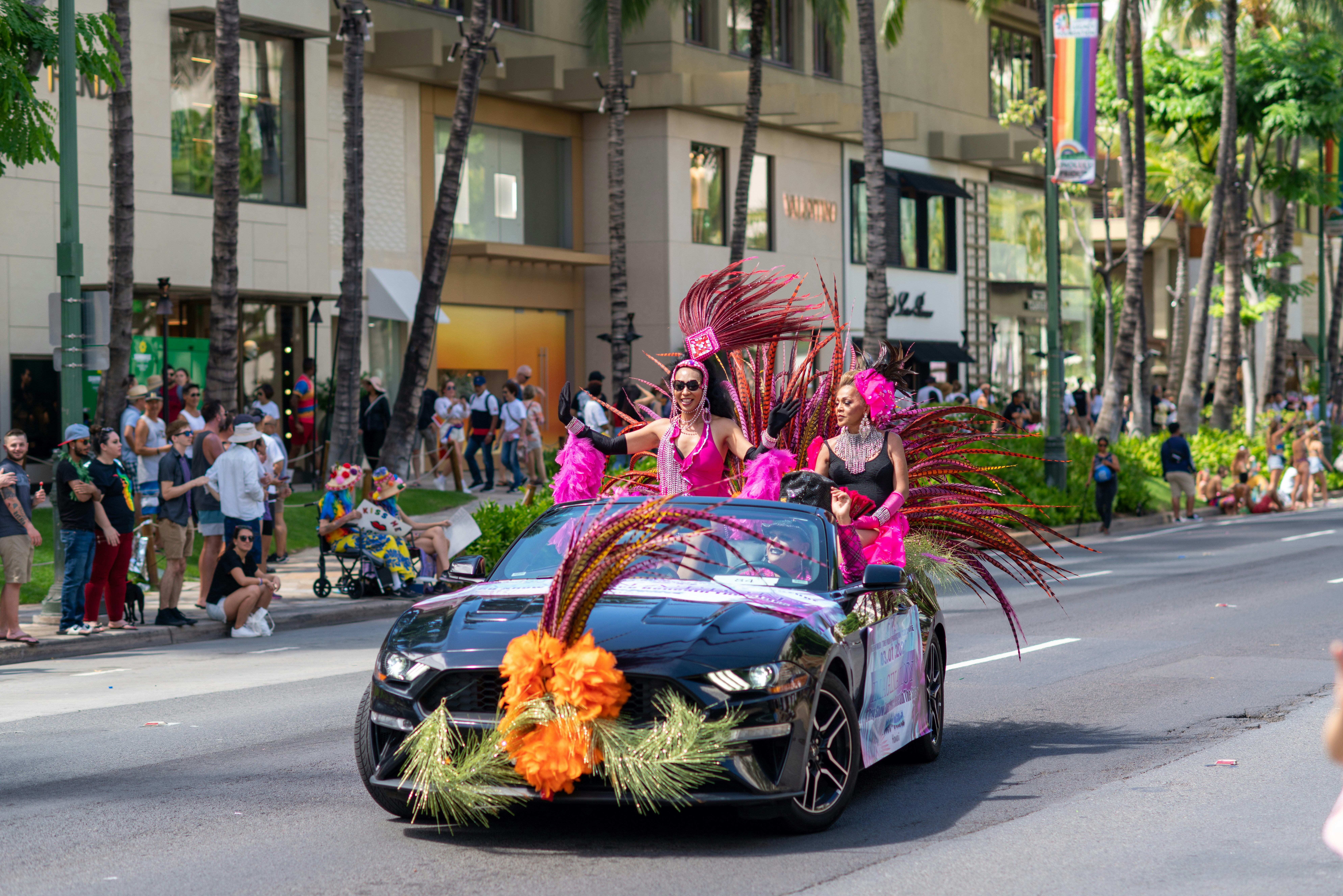 Colorful parade float adorned with tropical decorations and performers celebrating in a lively street atmosphere.