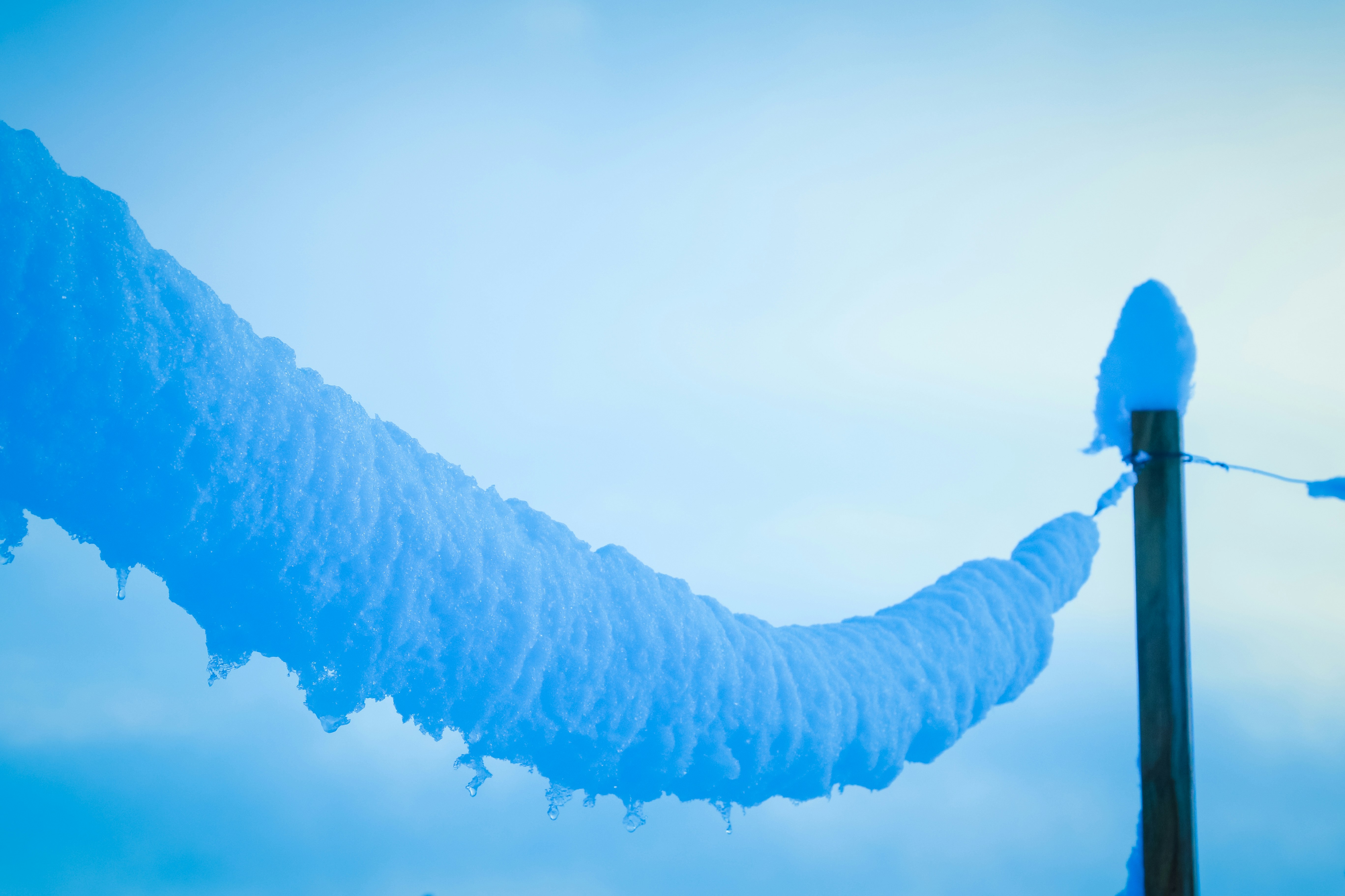 Blue Frost Ribbon: Snow-Covered Rope Reaches Toward a Quiet Post