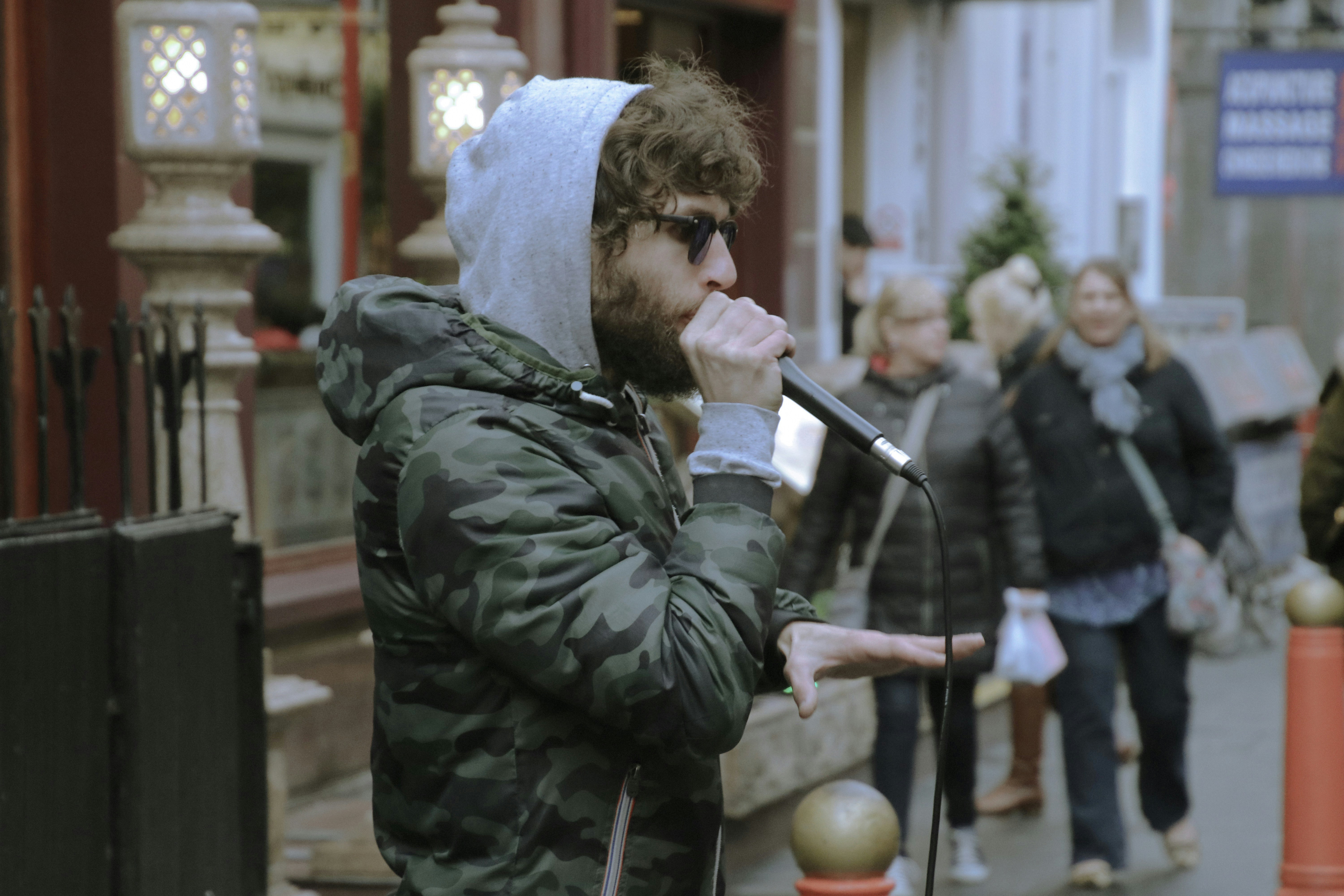 Man wearing green hooded jacket standing while rapping and people ...