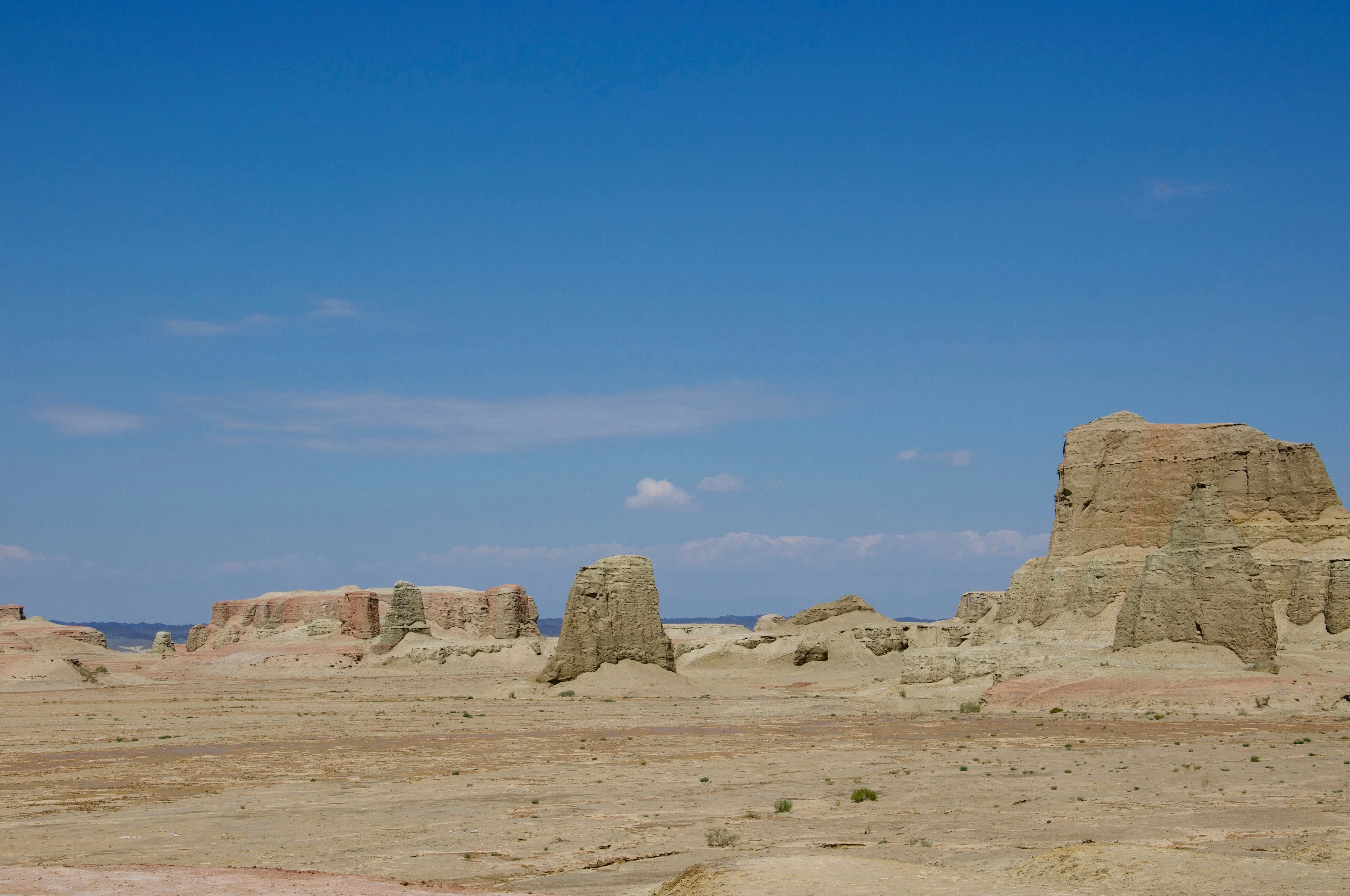 Desert landscape with rugged rock formations beneath a bright blue sky.
