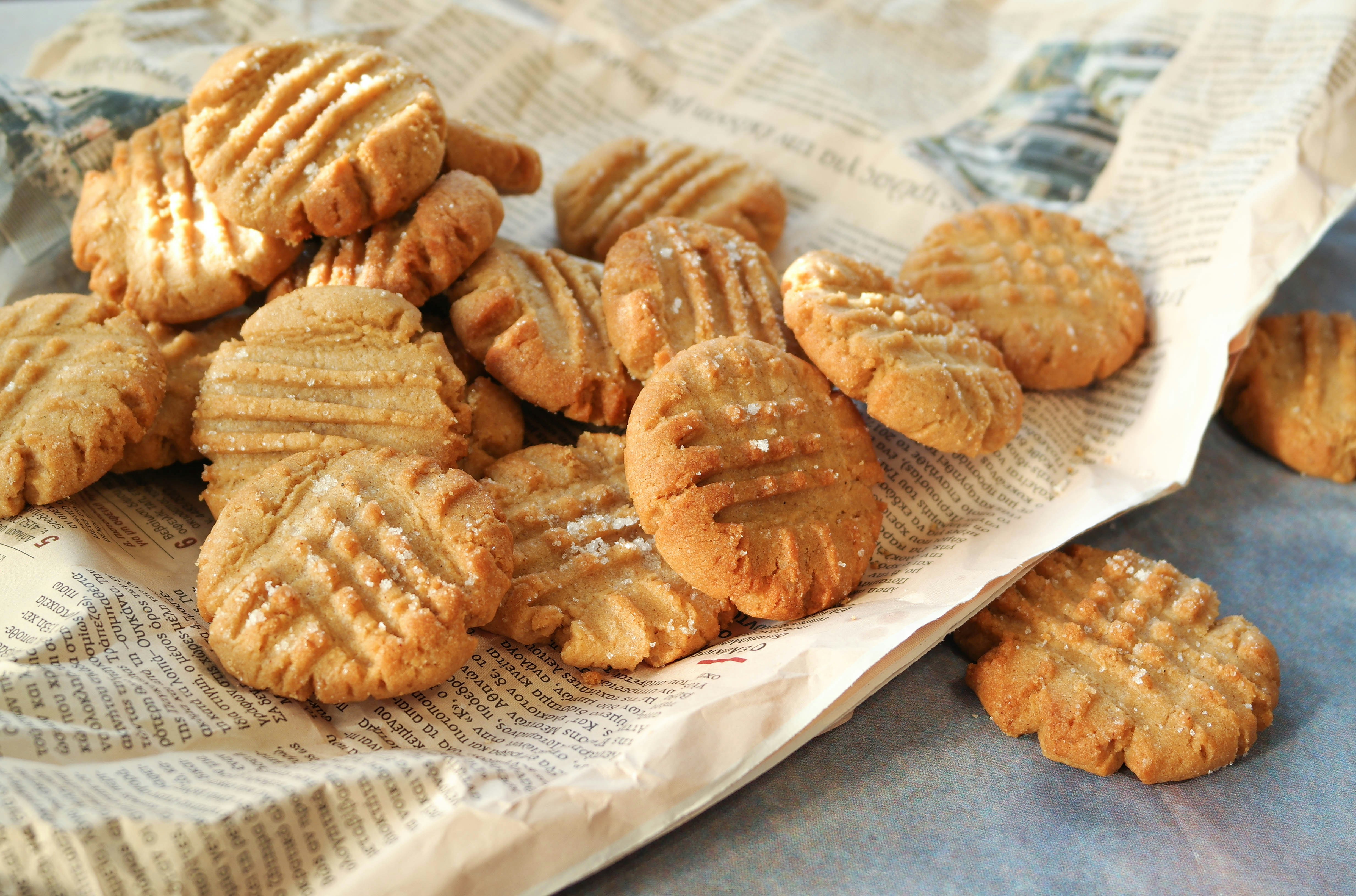 Freshly baked peanut butter cookies stacked on crumpled parchment paper.