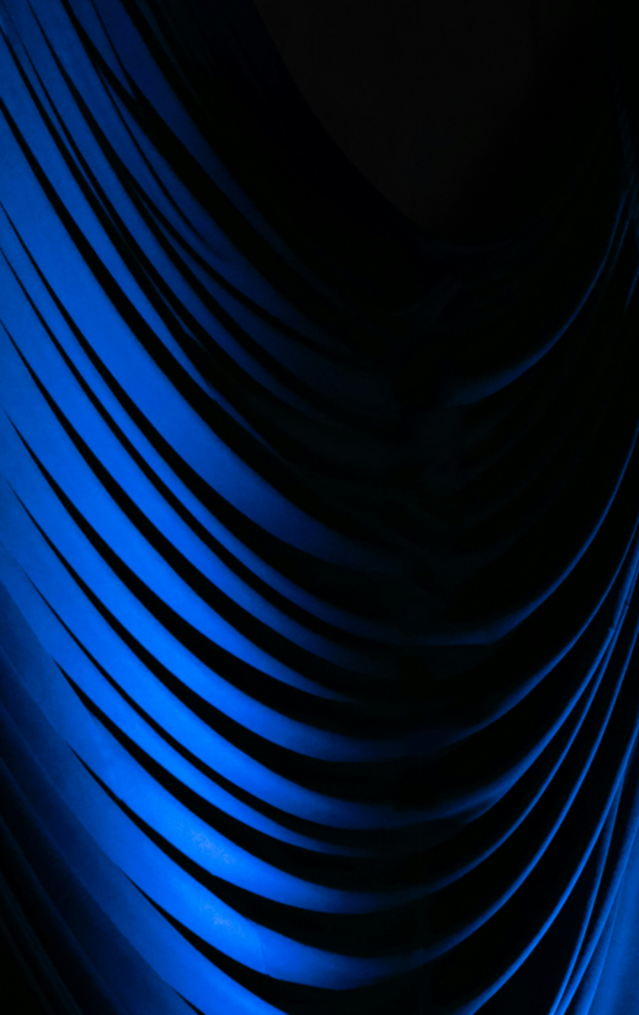 Flowing blue fabric illuminated against a dark background, creating a dramatic interplay of texture and color.