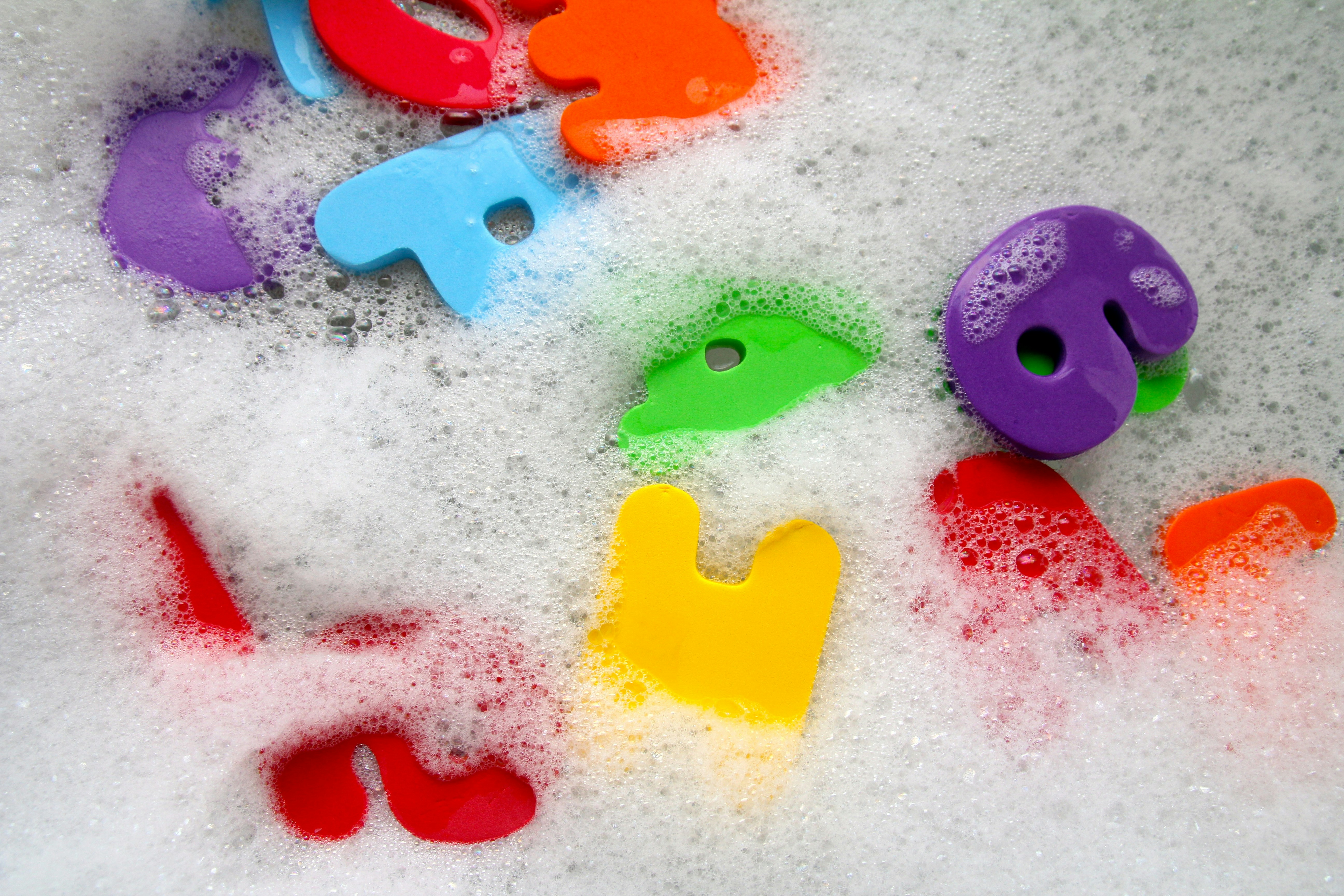Color Mosaic in Frothy Bath: A Close-Up of Playful Plastic Shapes