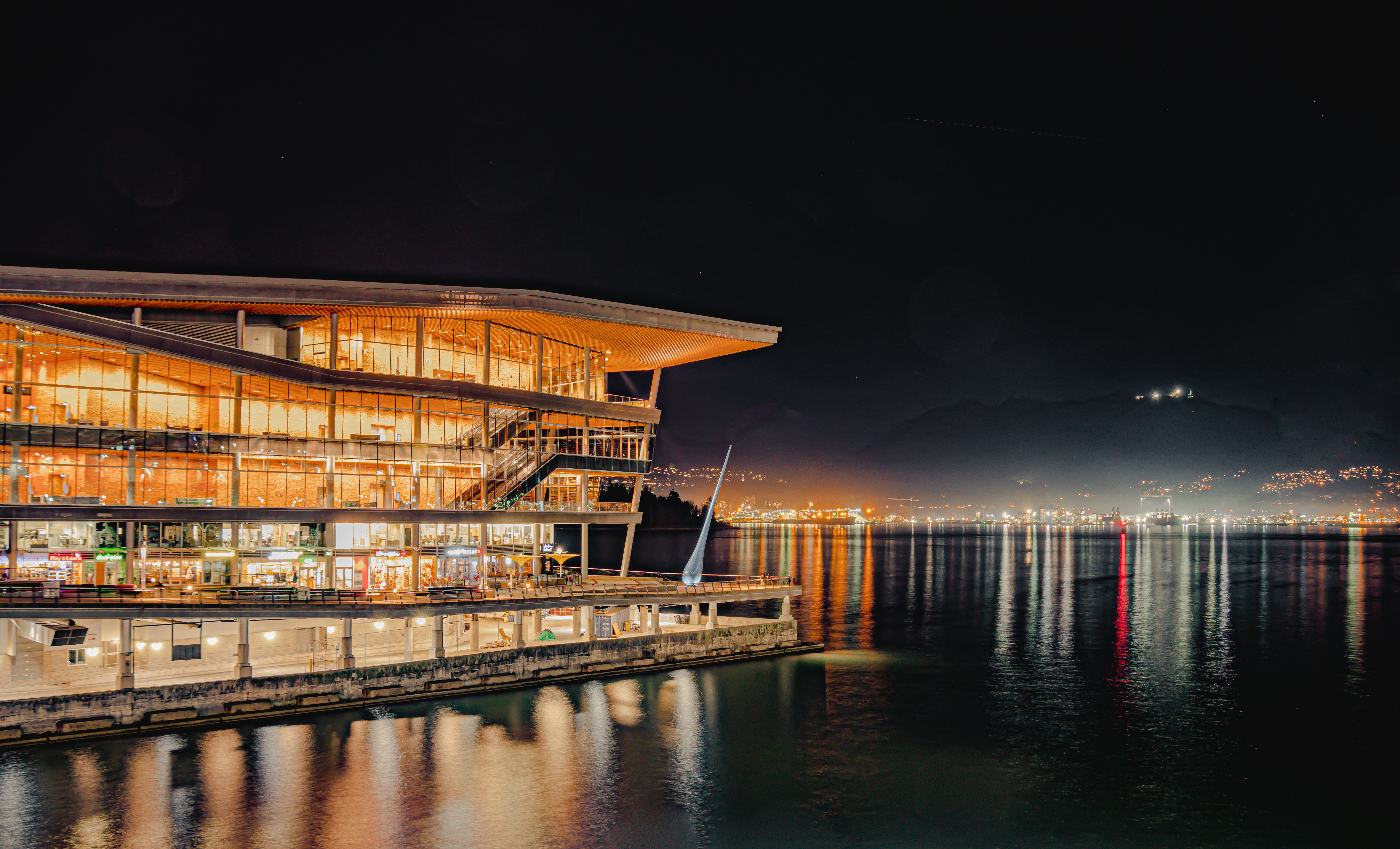 A building on the edge of a body of water at night photo – Free Brown ...