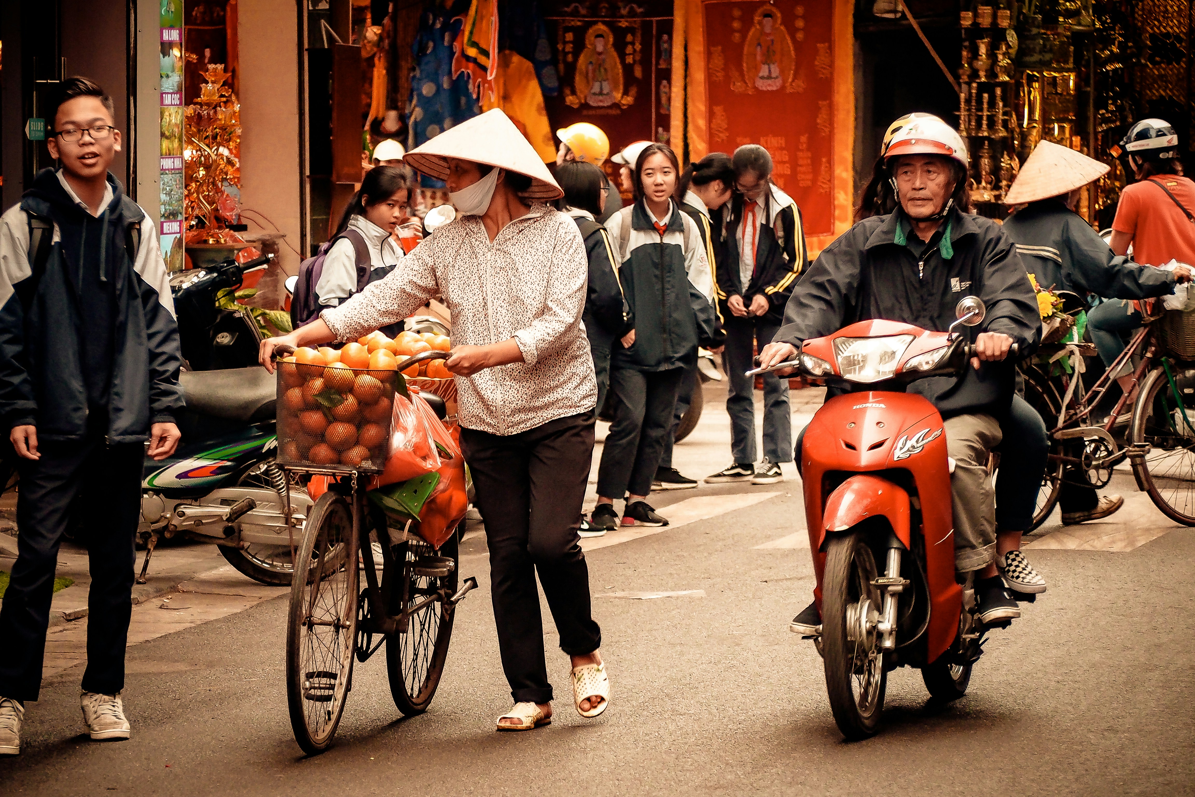 Individuals navigating a bustling Hanoi street with motorbikes and bicycles.