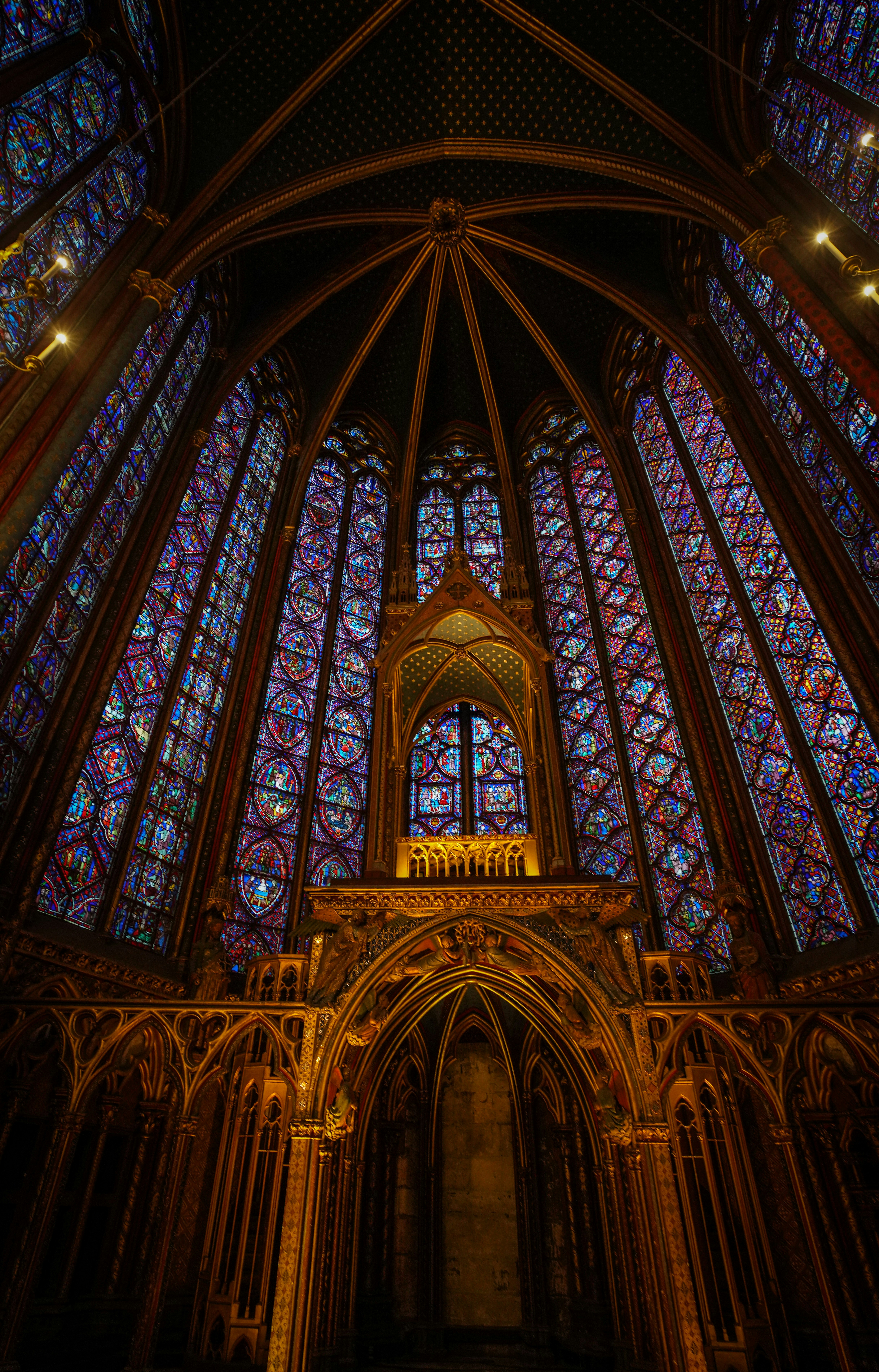 Intricate stained glass windows illuminate the gothic architecture of a historic chapel, showcasing vibrant colors and detailed craftsmanship.