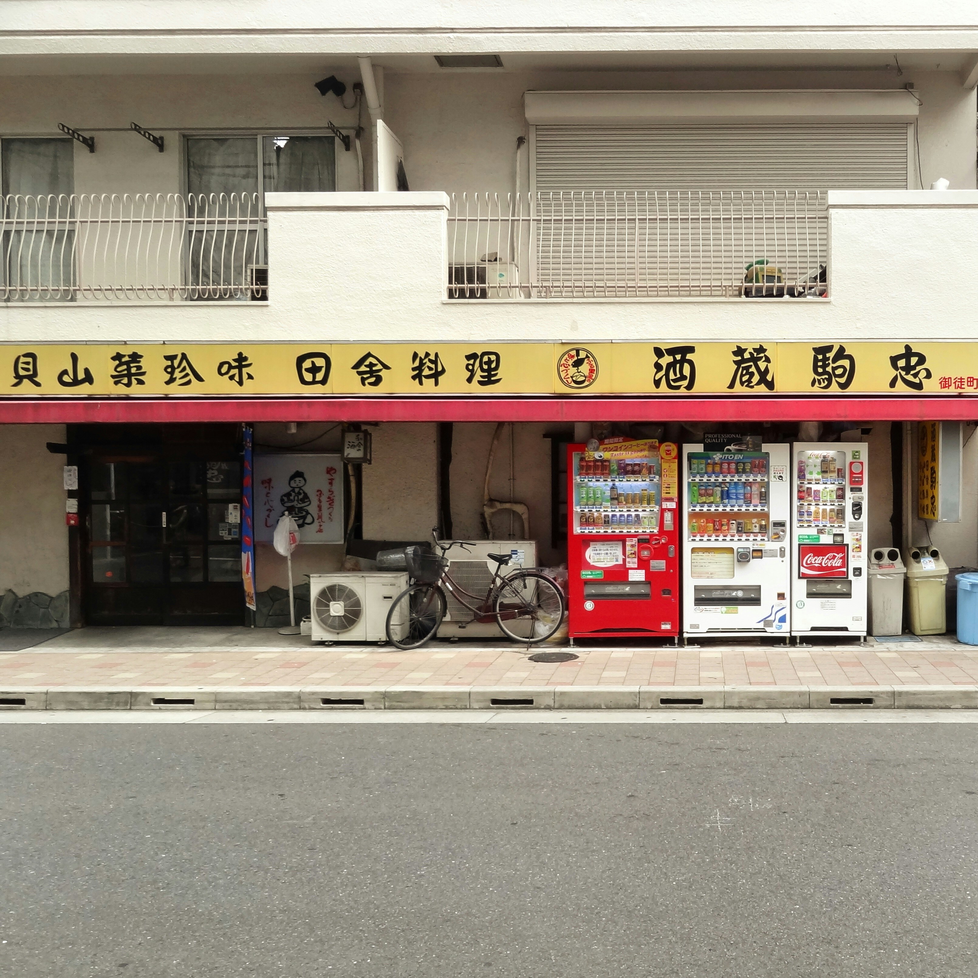 Traditional eatery with vibrant signage and vending machines in an urban setting, showcasing local culture and convenience.