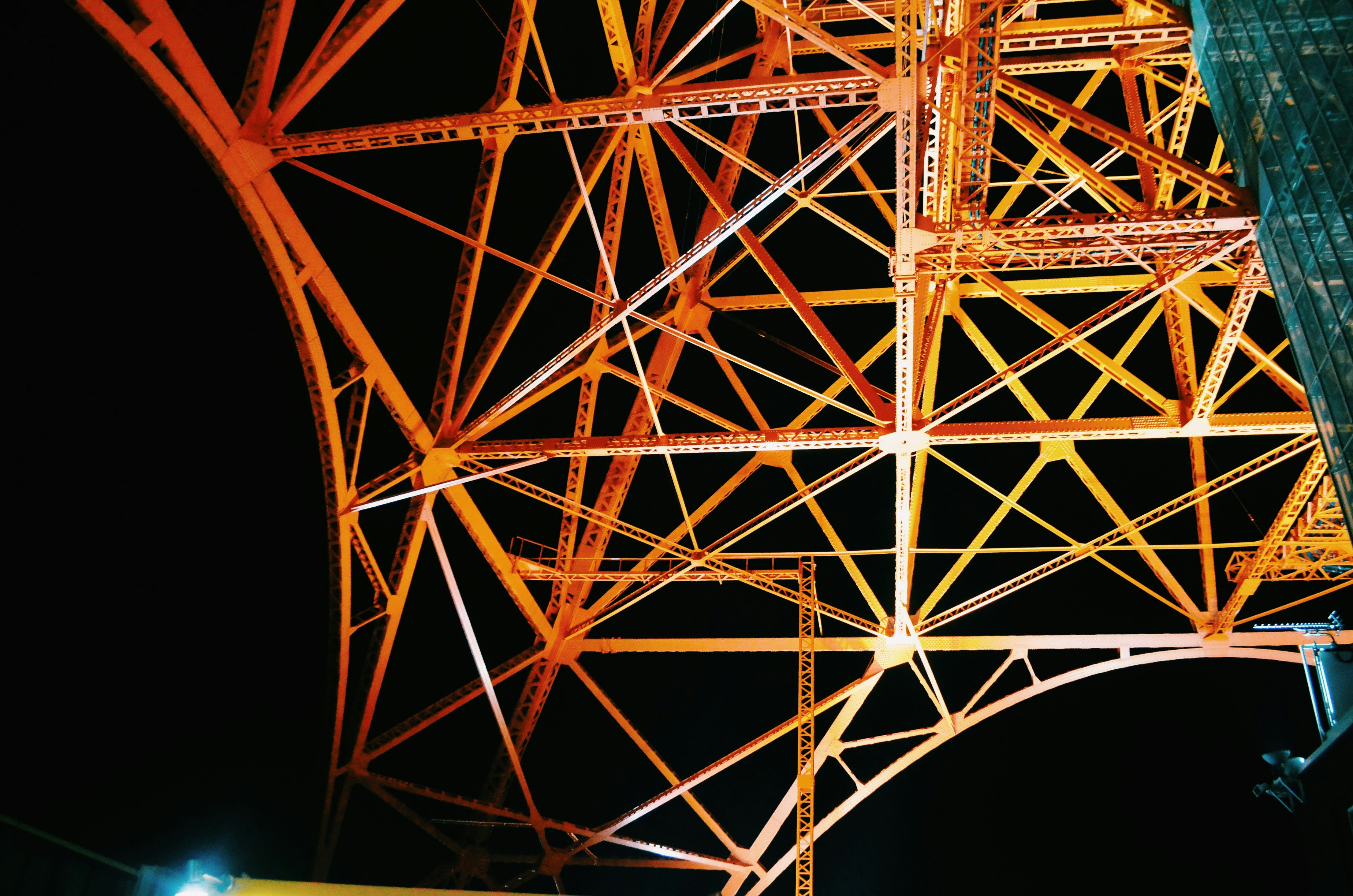 Intricate framework of Tokyo Tower illuminated against the night sky, showcasing its bold orange structure and geometric design.