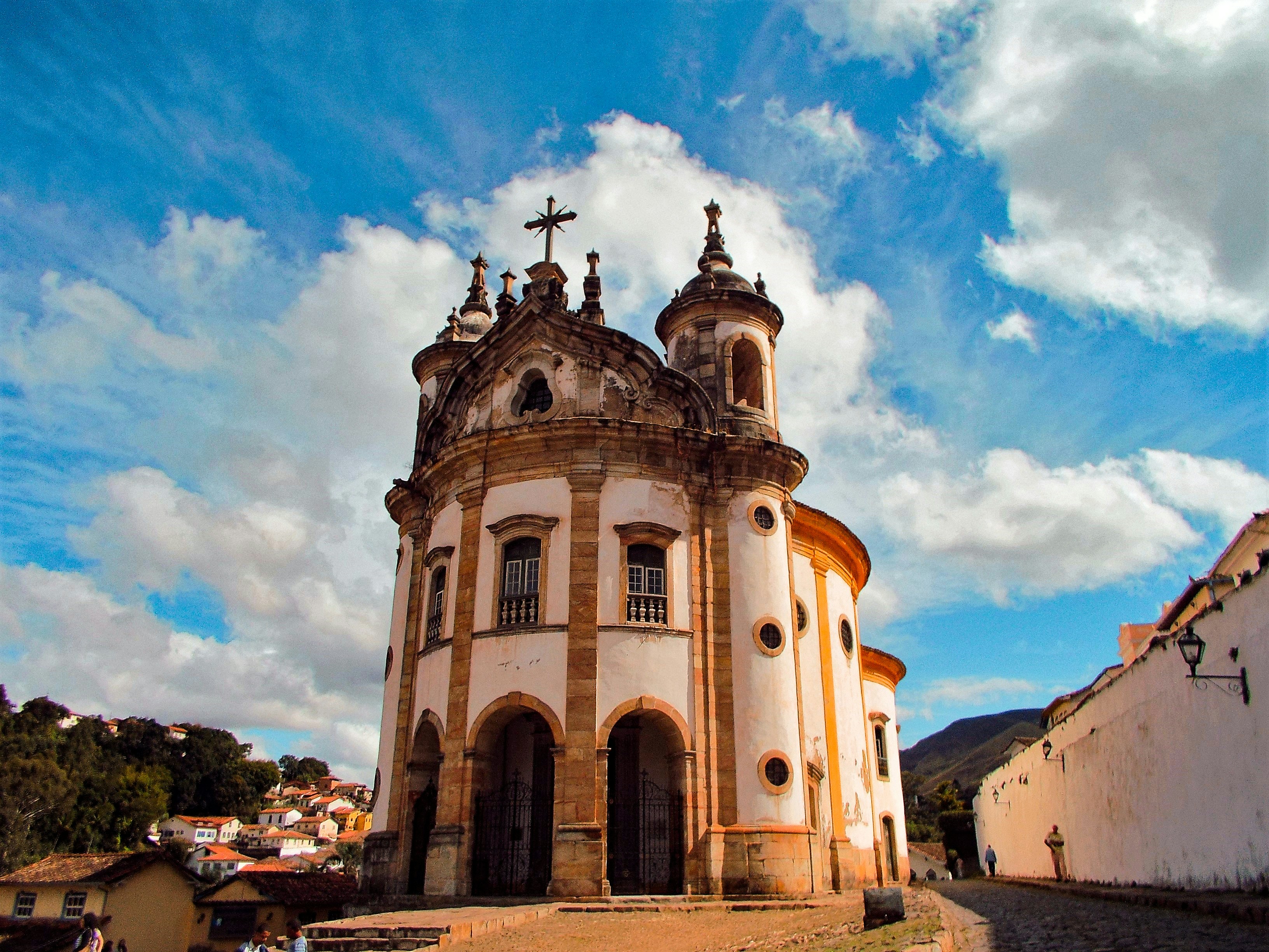 Historic baroque church with ornate towers set against a vibrant blue sky and white clouds.