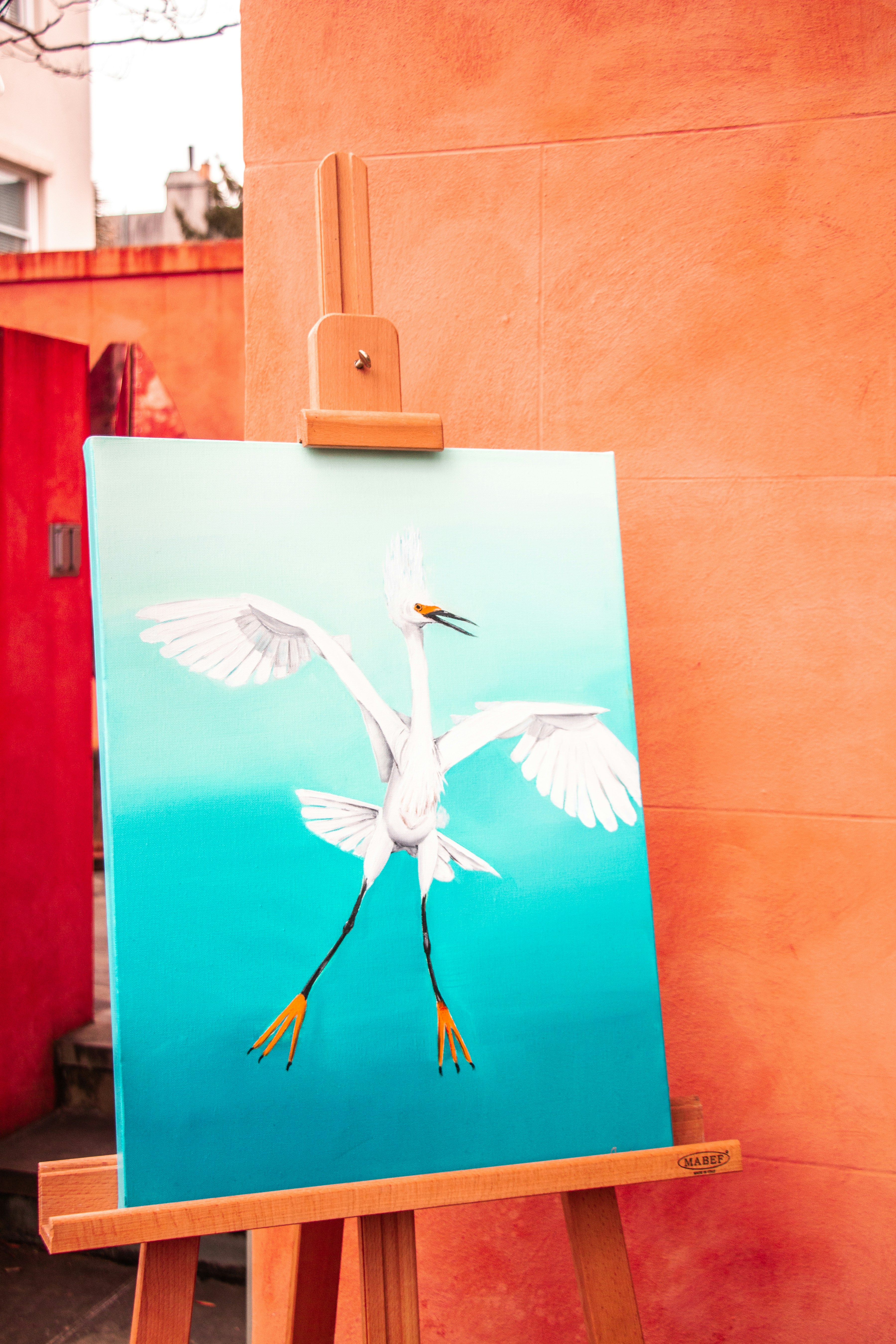 Crane’s Flight Across a Cerulean Canvas on a Terracotta Stage