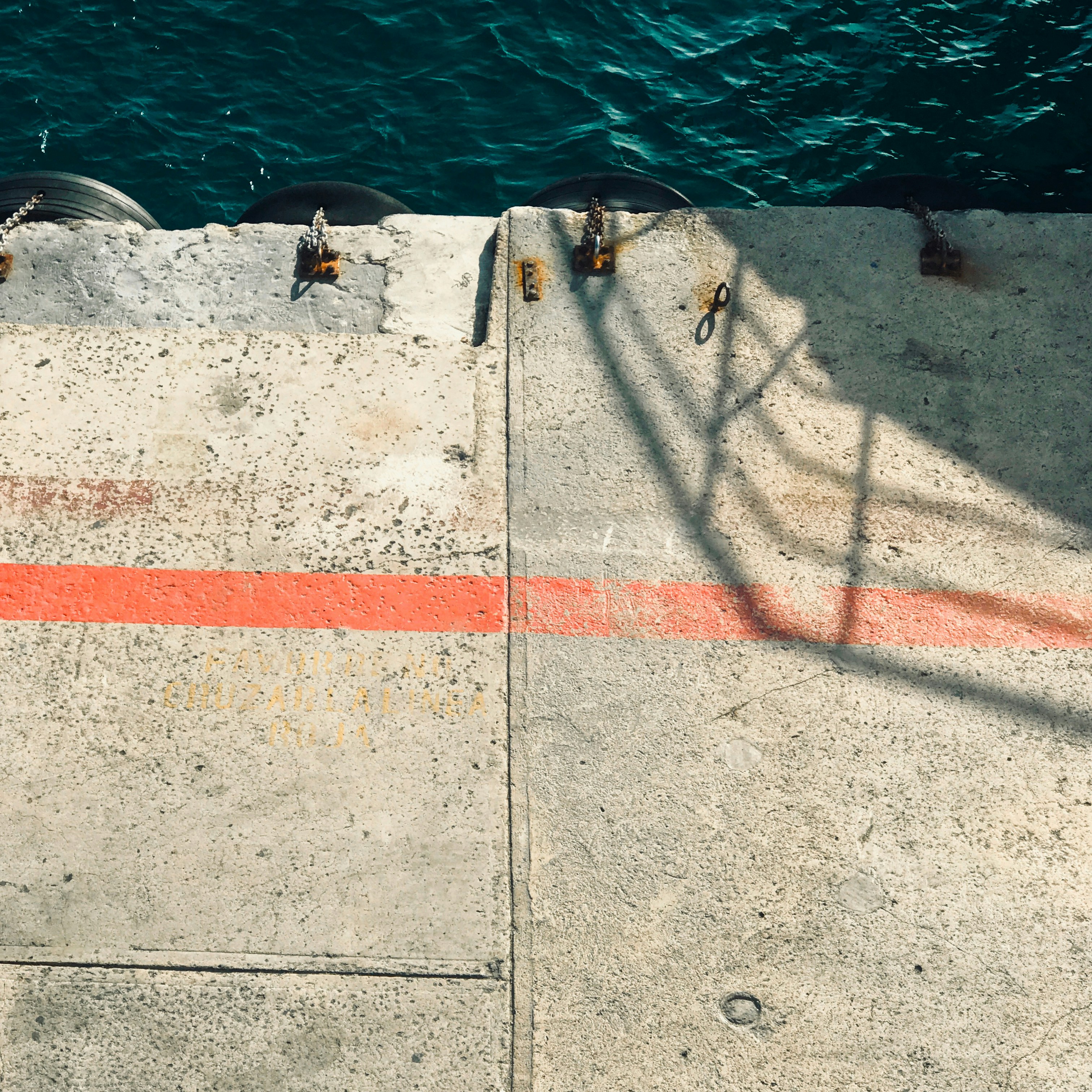 Red Stripe at the Edge: Shadowed Geometry on a Weathered Dock