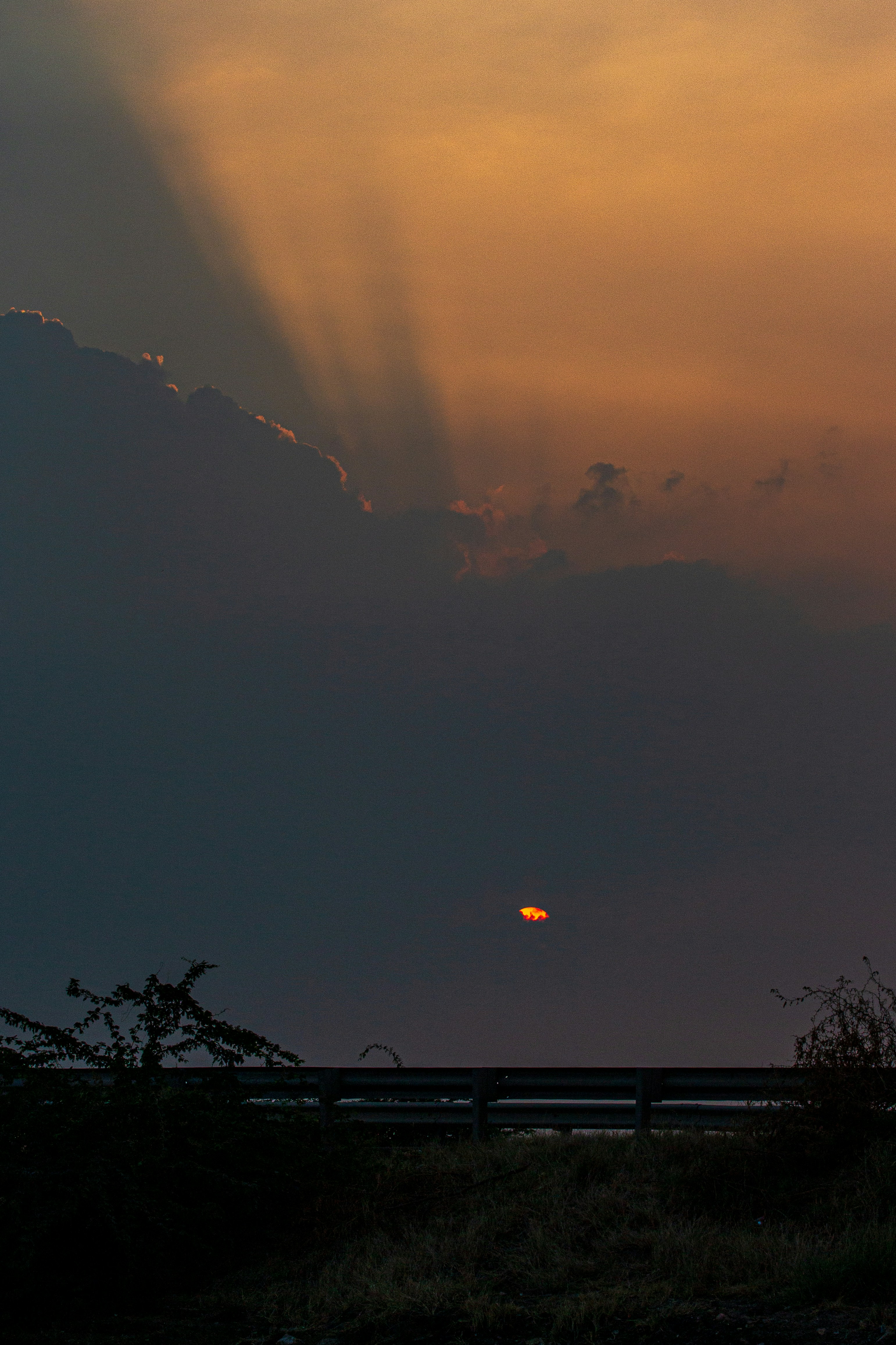 Sunset Silhouette: Rays Through Twilight Clouds