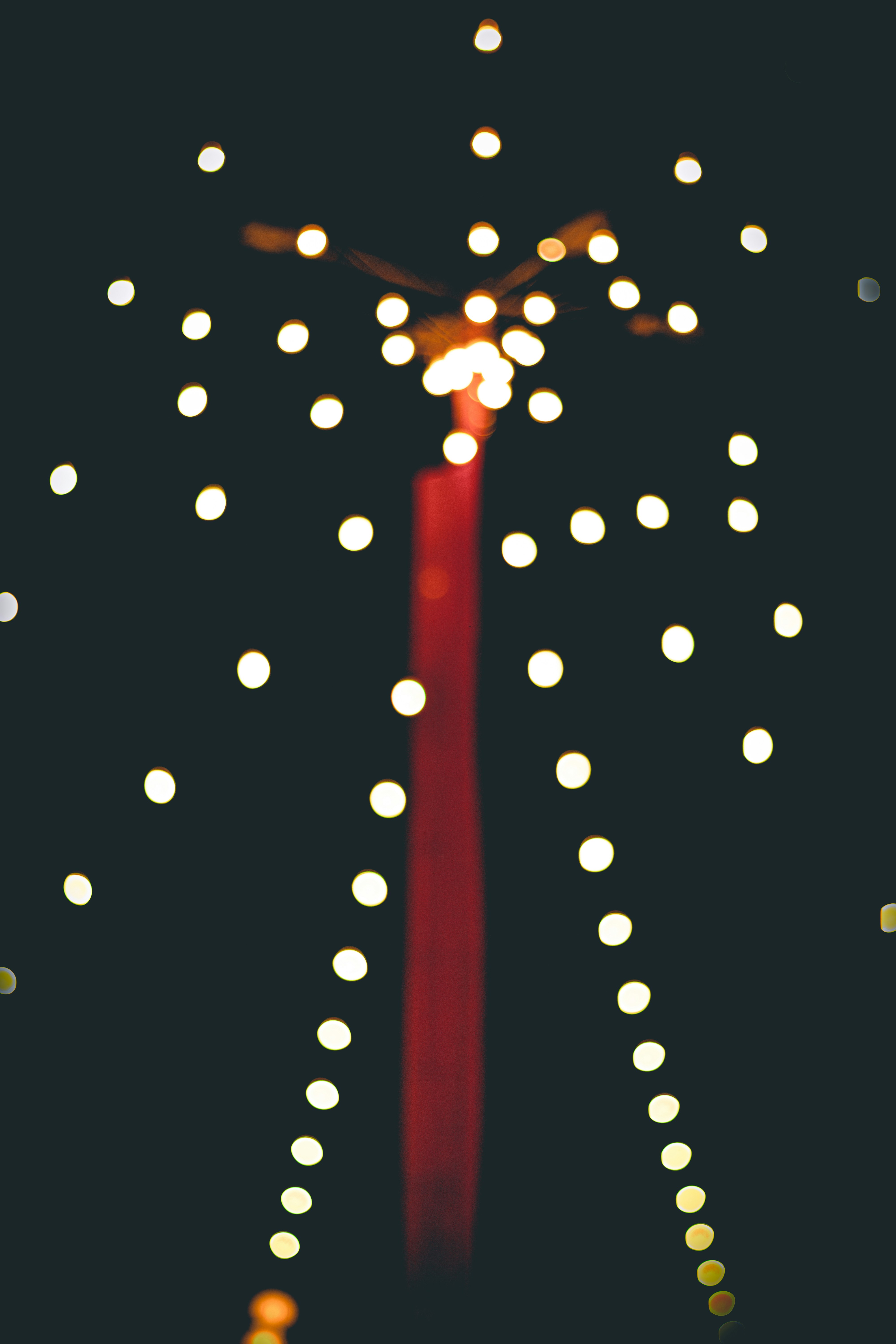 Ember Vertical: A Red Sparkler Woven Through Night-Glow Orbs