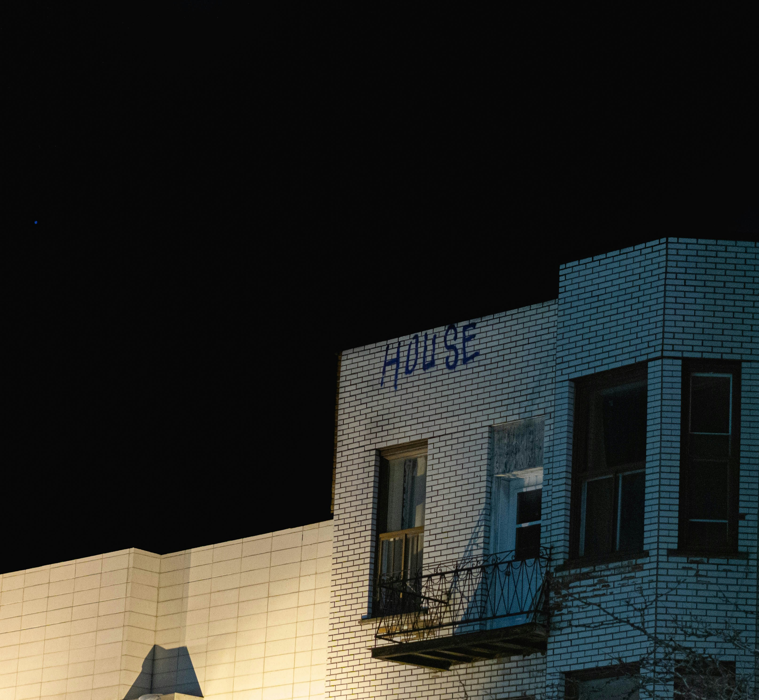 Blue HOUSE Sign on a Night-Burnished Brick Corner