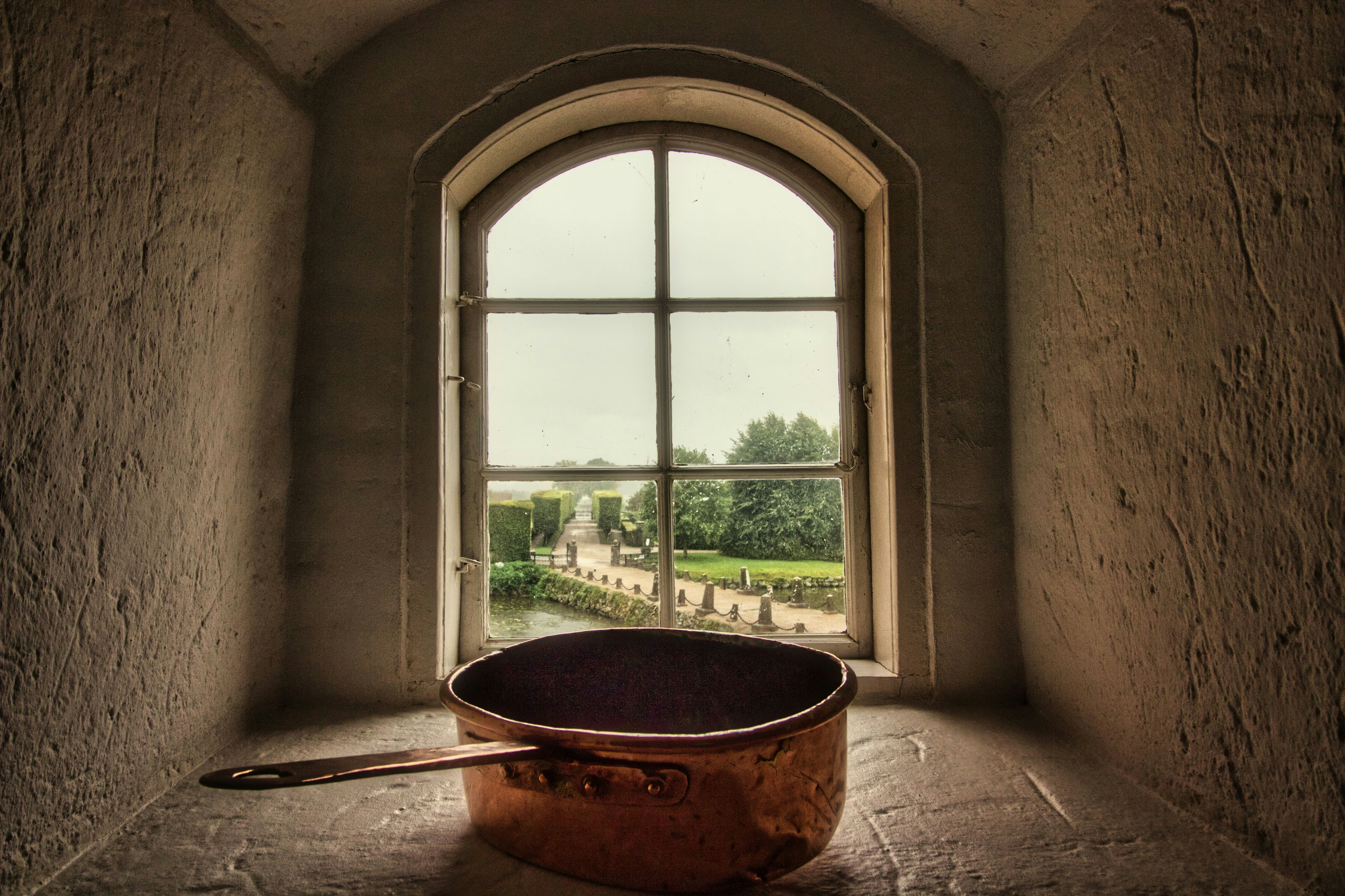 Copper Pot on a Sun-Warmed Window Sill Framing a Quiet Garden