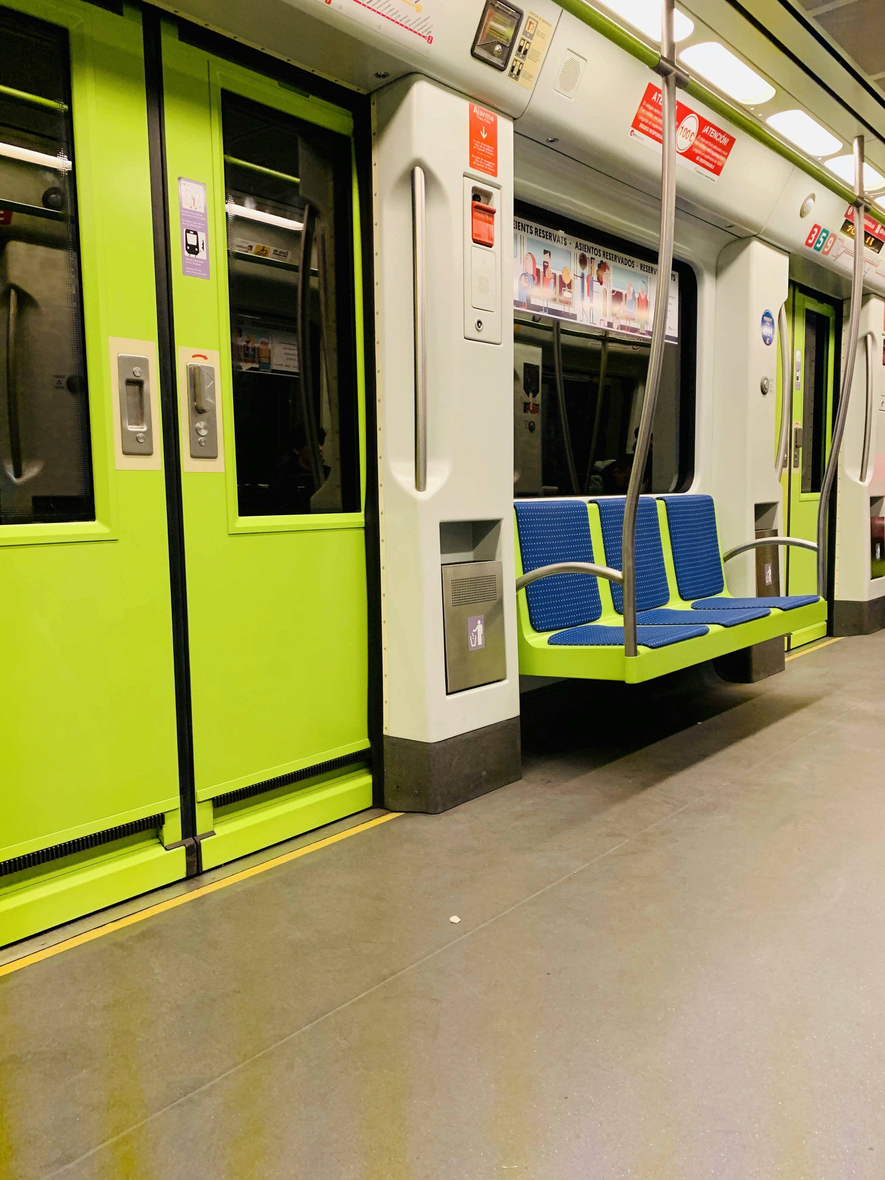 Interior of an empty subway car featuring lime-green doors and blue cushioned seats, highlighting the clean, orderly urban transit space.
