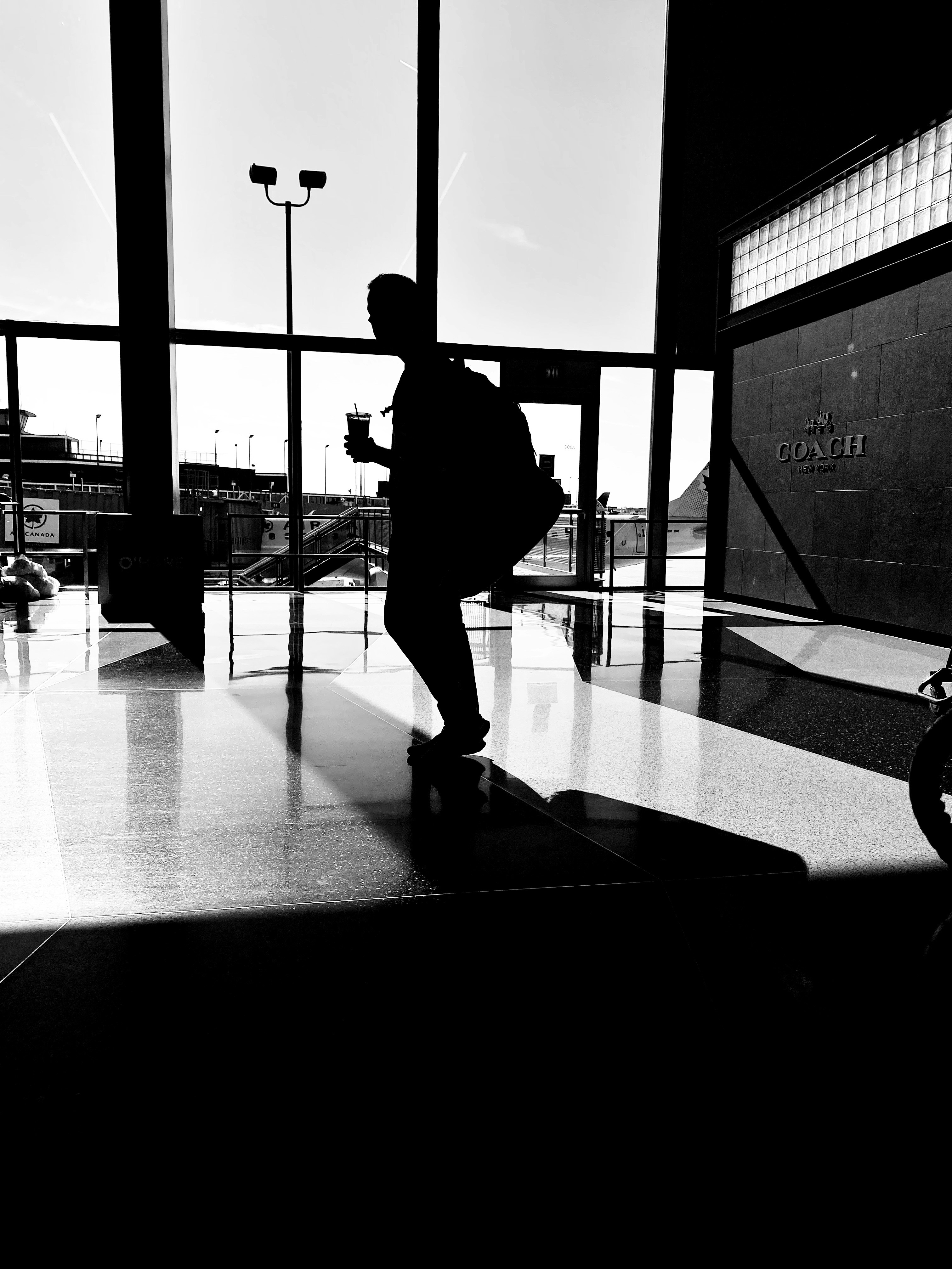 Glass Atrium Silence: A Lone Silhouette Steps Through Backlight