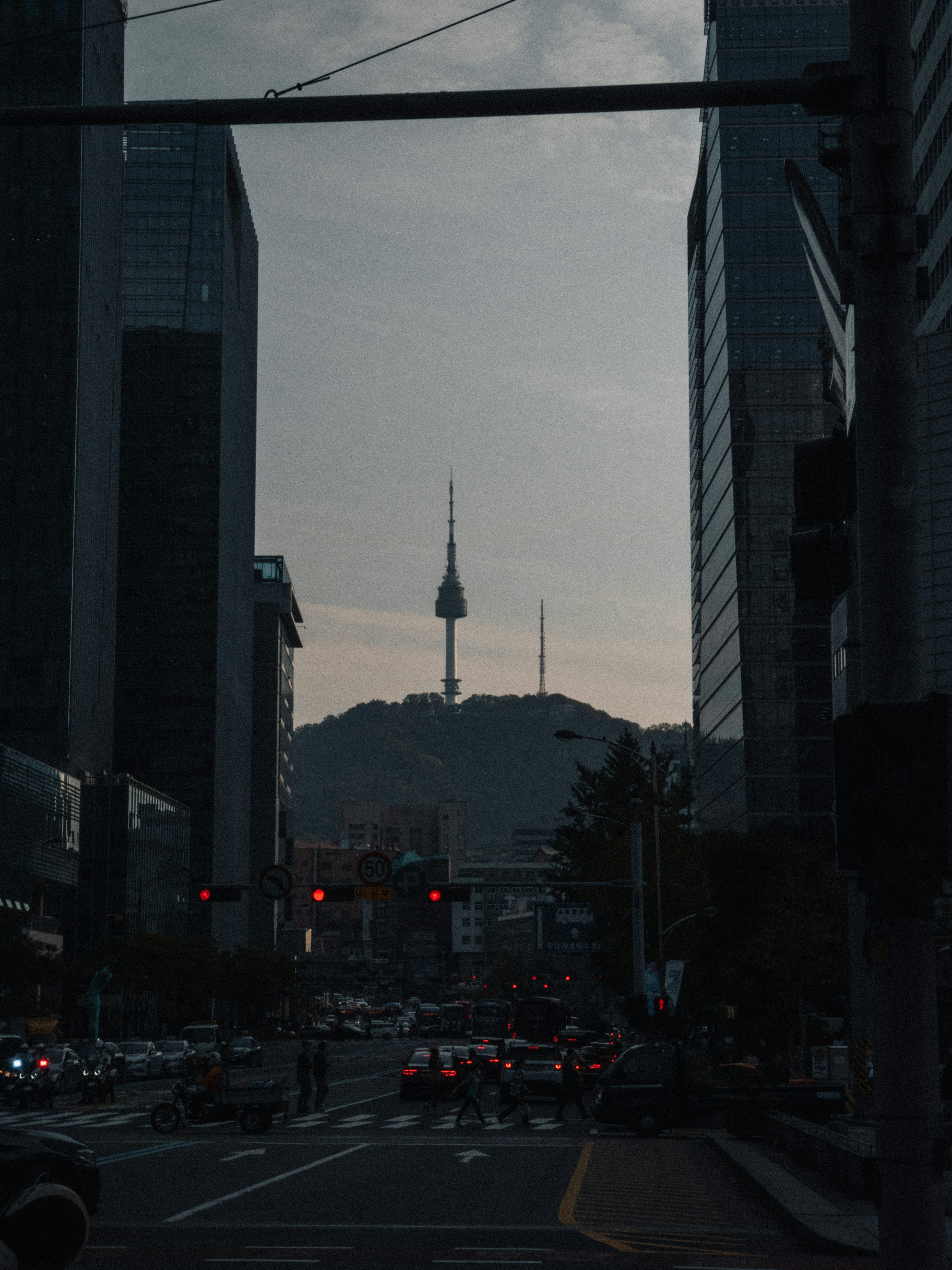 Dusk Over Seoul: Namsan Tower Rising Beyond a Glass-Canyon Street