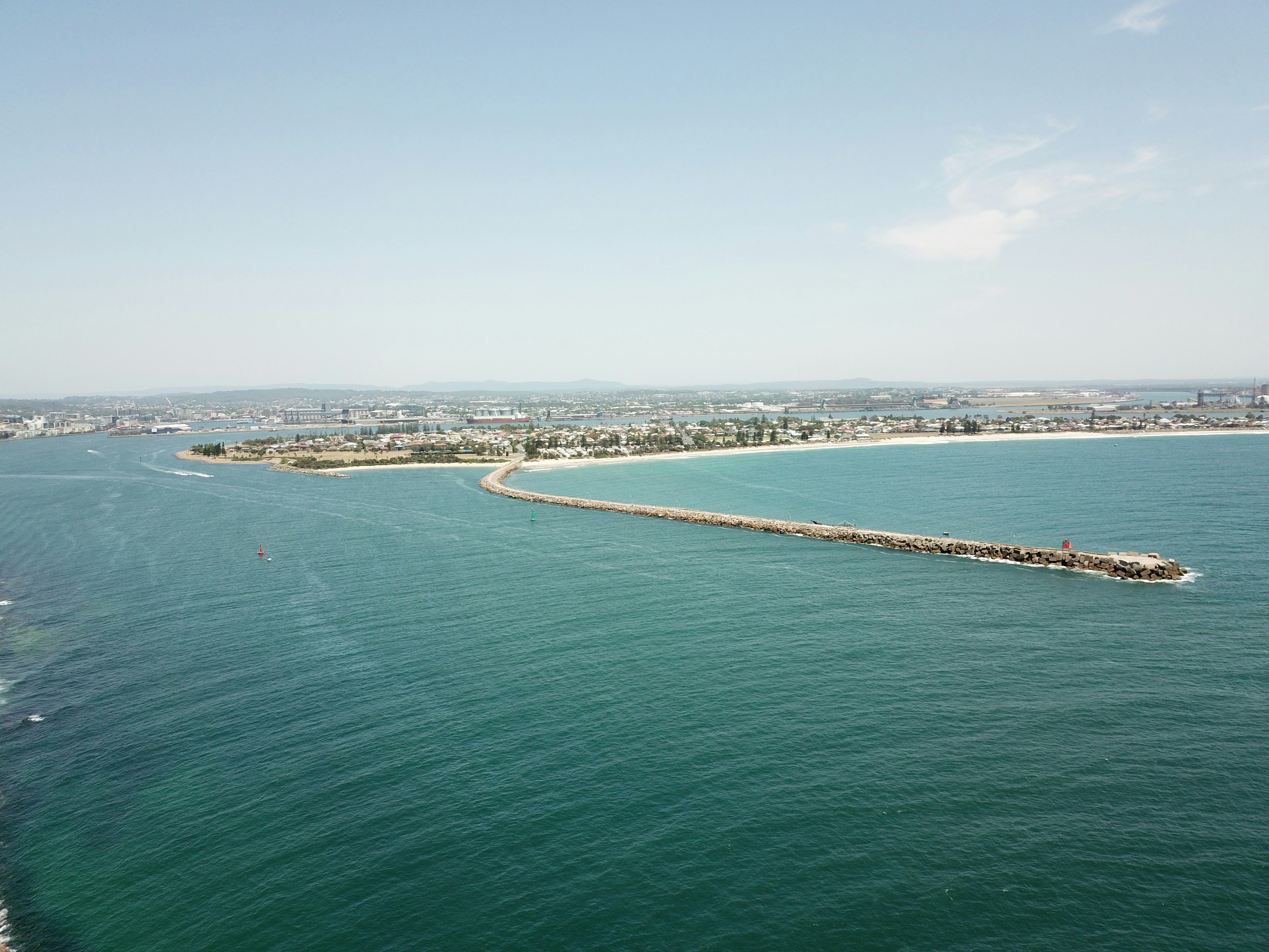 Aerial view of Stockton Breakwall extending into the ocean under a clear sky.