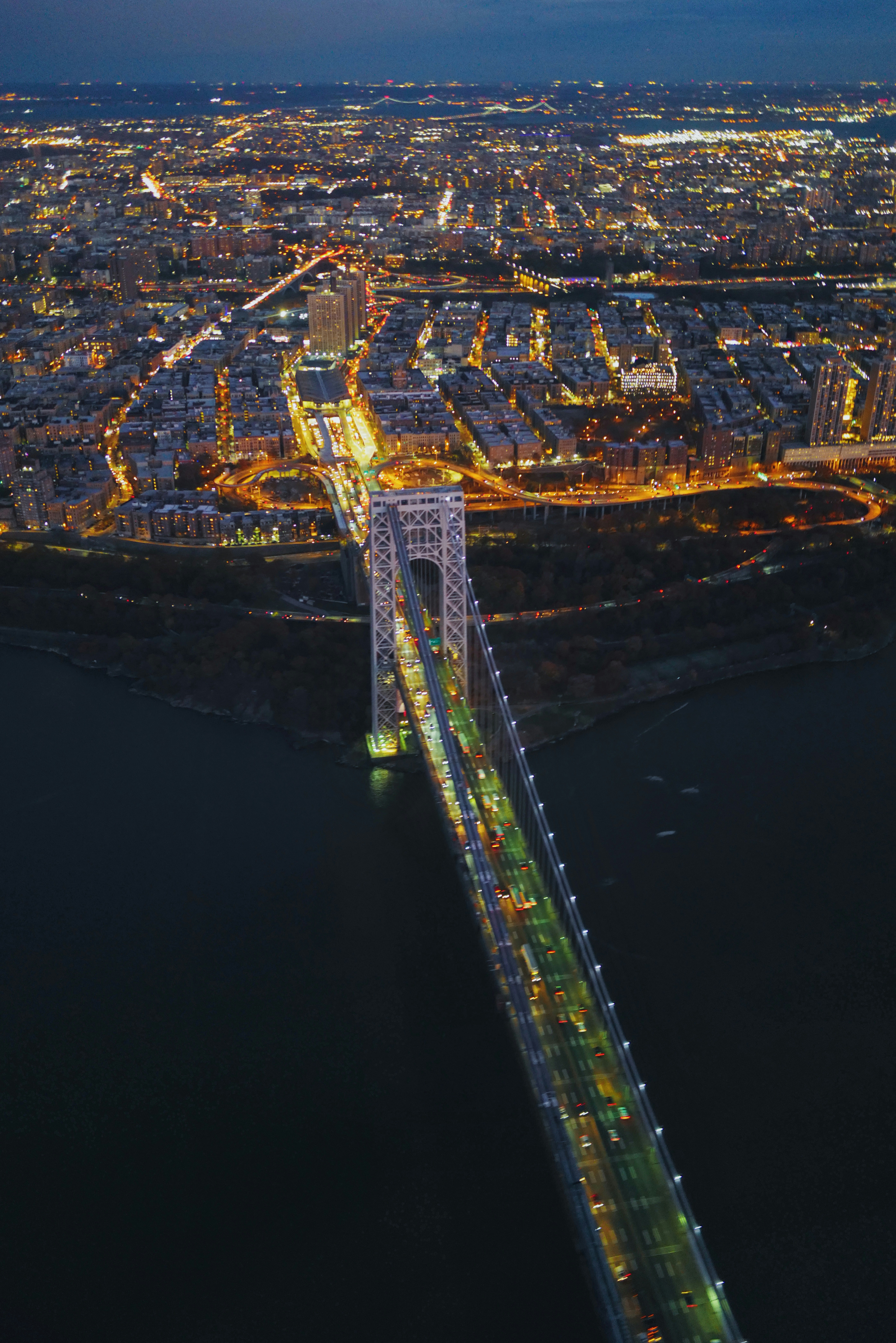 Aerial view of the George Washington Bridge illuminated against the backdrop of a vibrant cityscape at twilight.