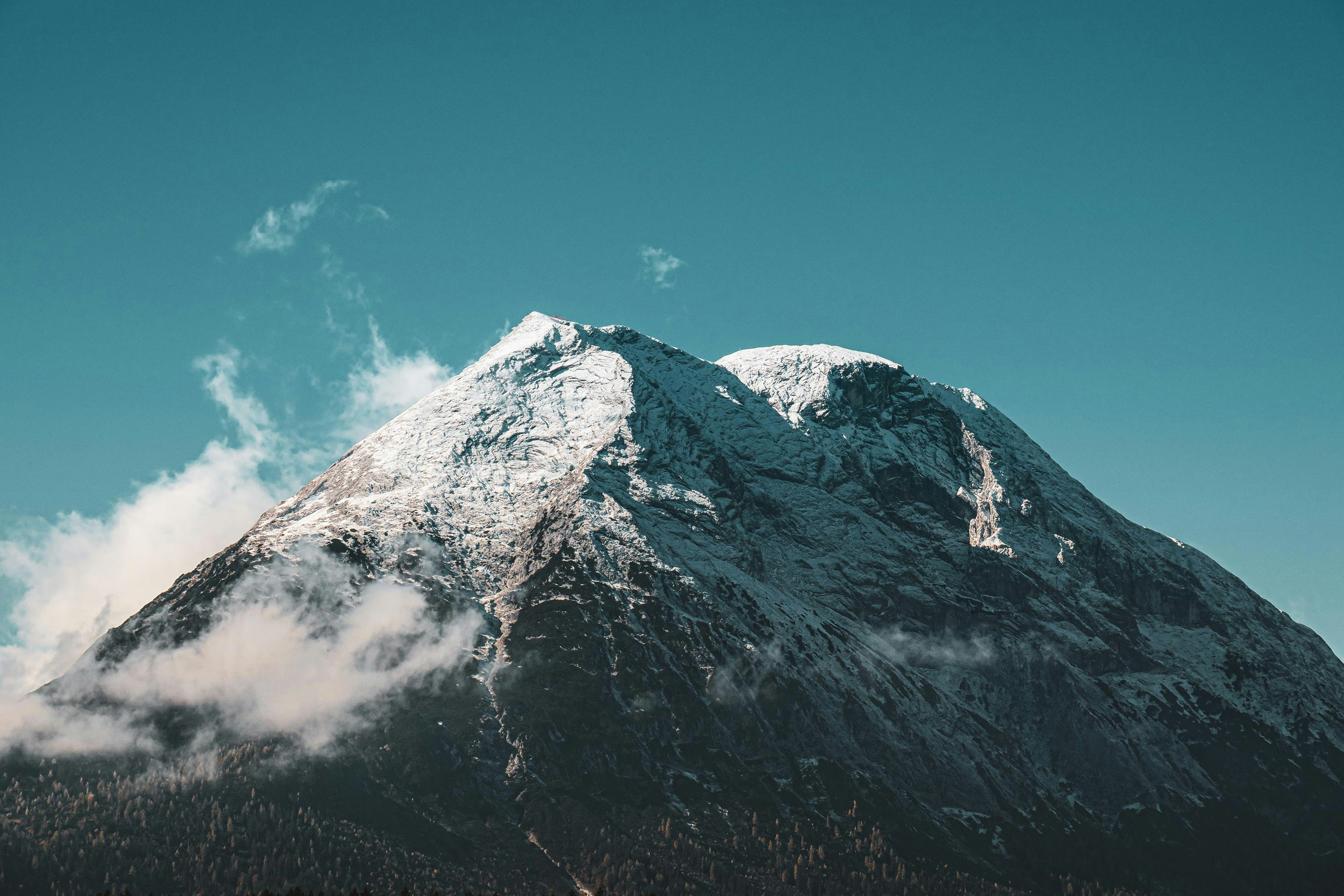 Snow-dusted mountain peak in Tirol under a clear blue sky.