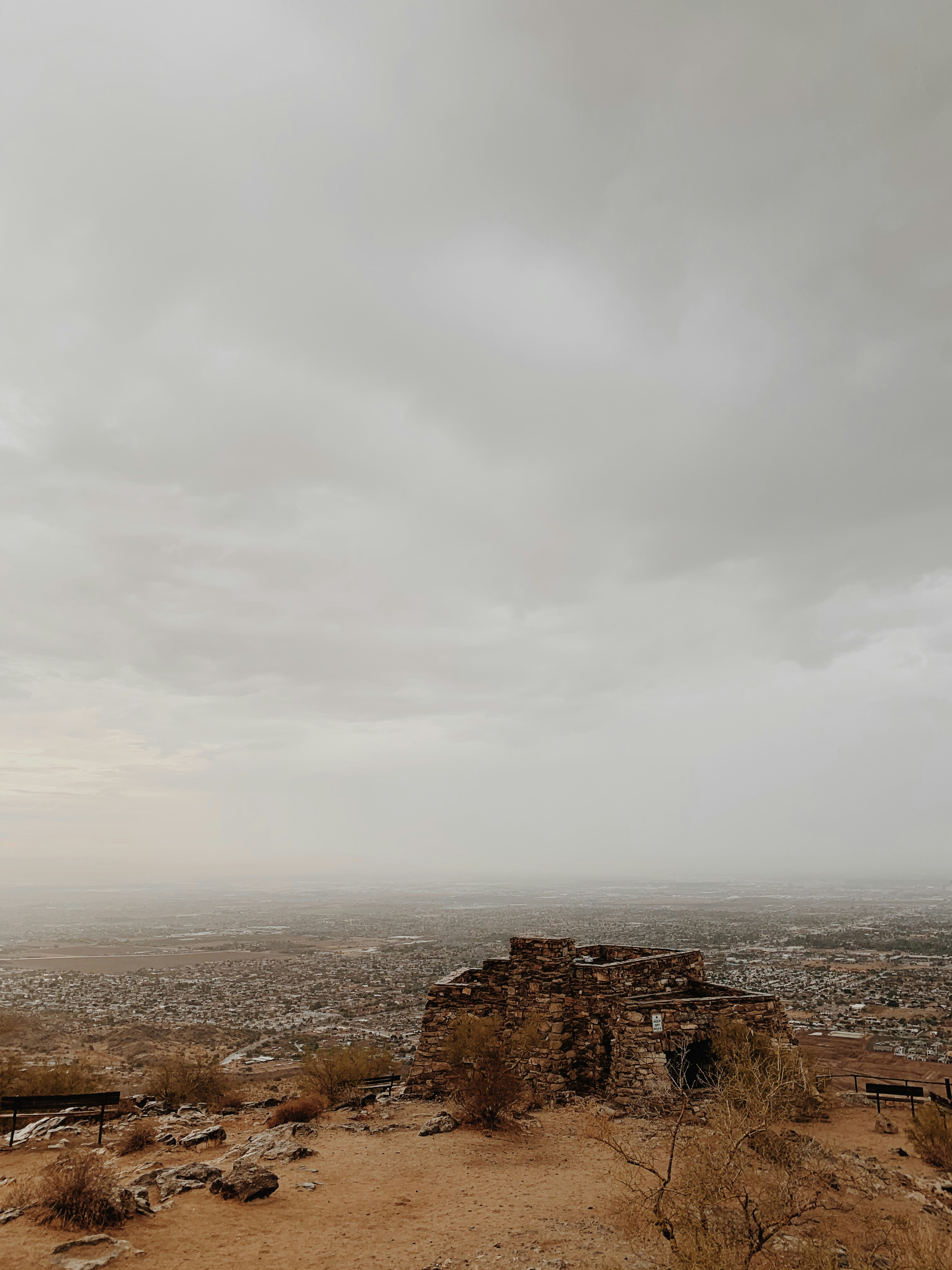Weathered stone ruins stand against a vast desert landscape under an overcast sky, hinting at stories long forgotten.