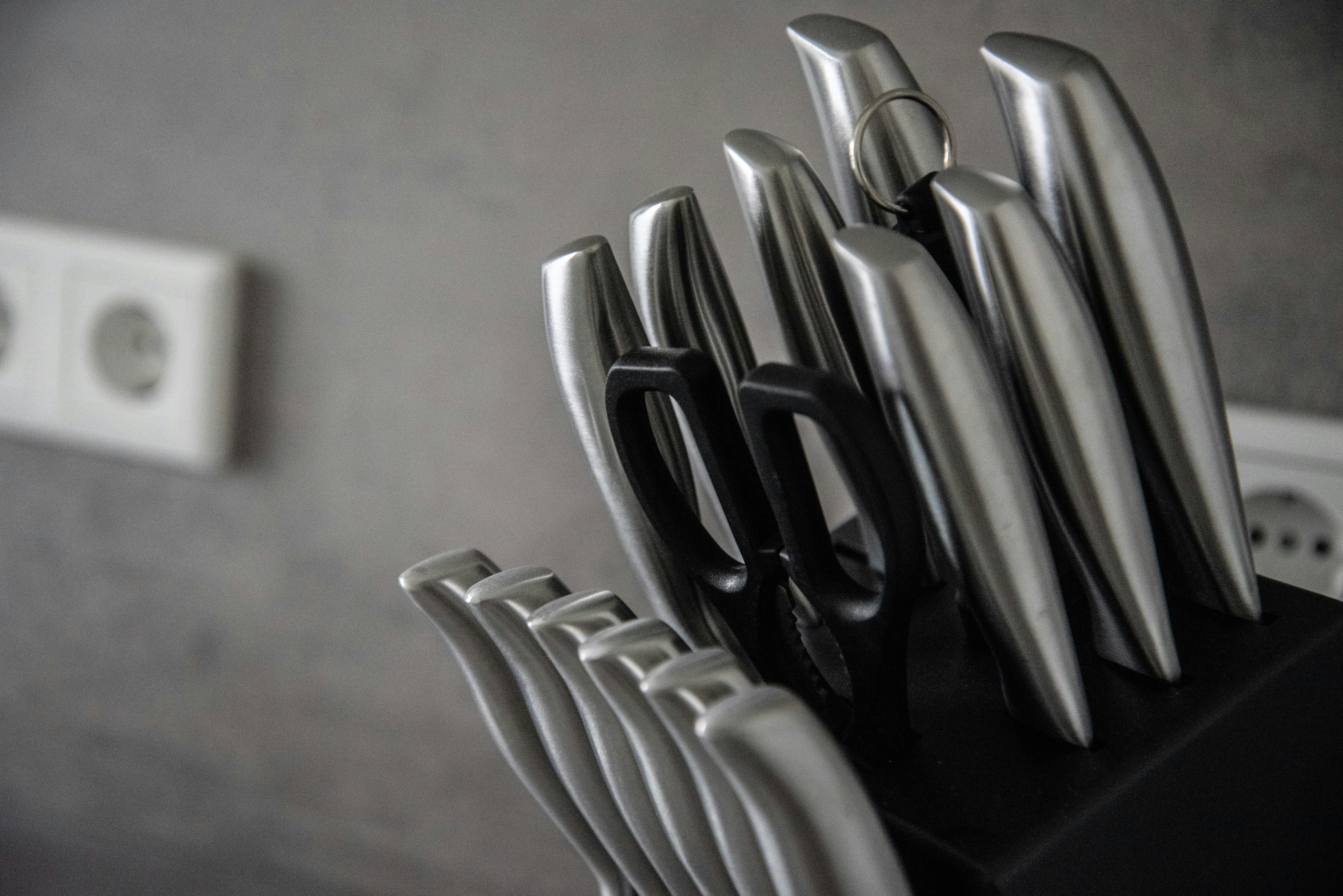 A modern knife block showcasing a variety of sleek stainless steel knives and scissors, emphasizing contemporary kitchen design.