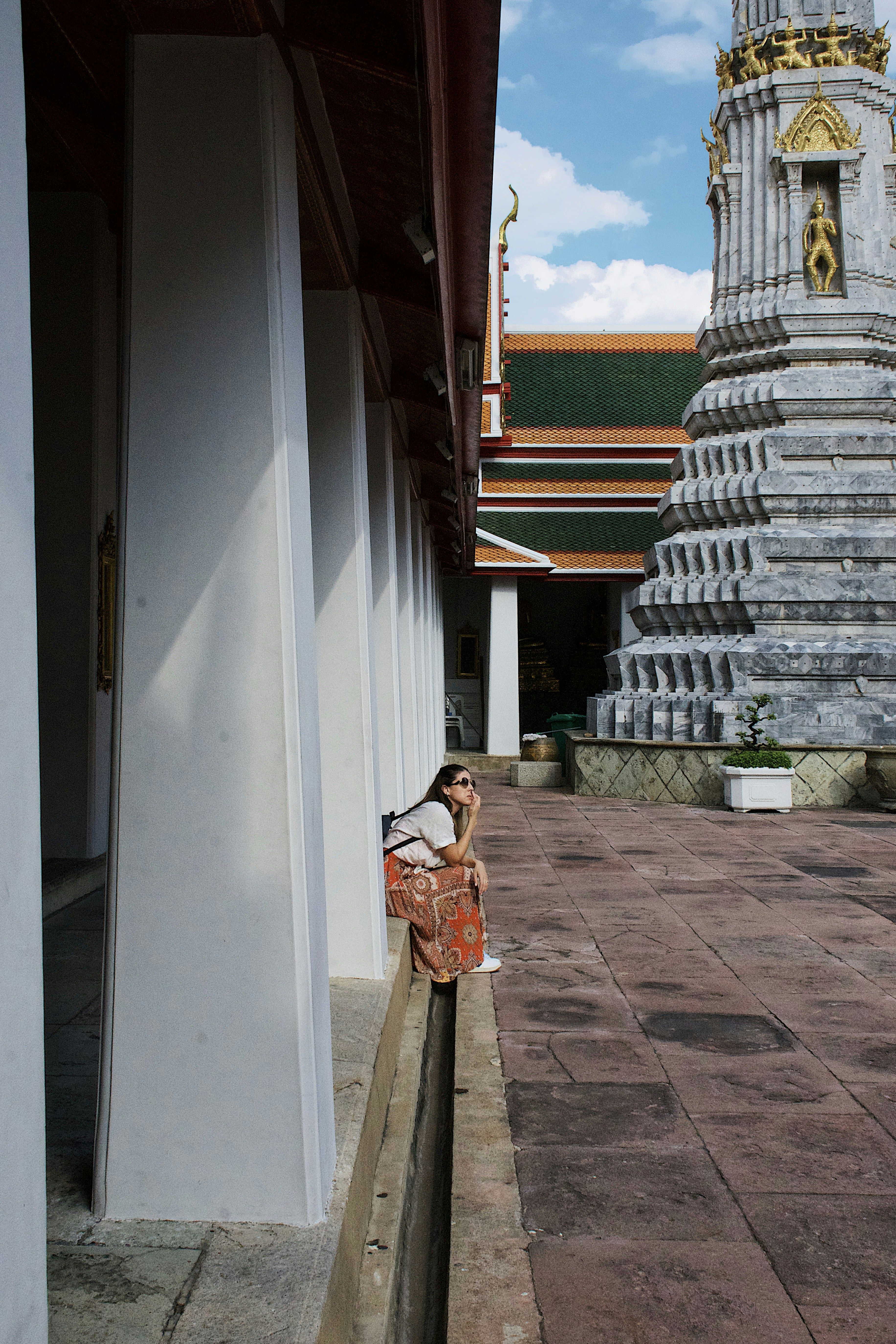 Temple Courtyard Quiet: A Seated Moment by the Colonnade and Stupa
