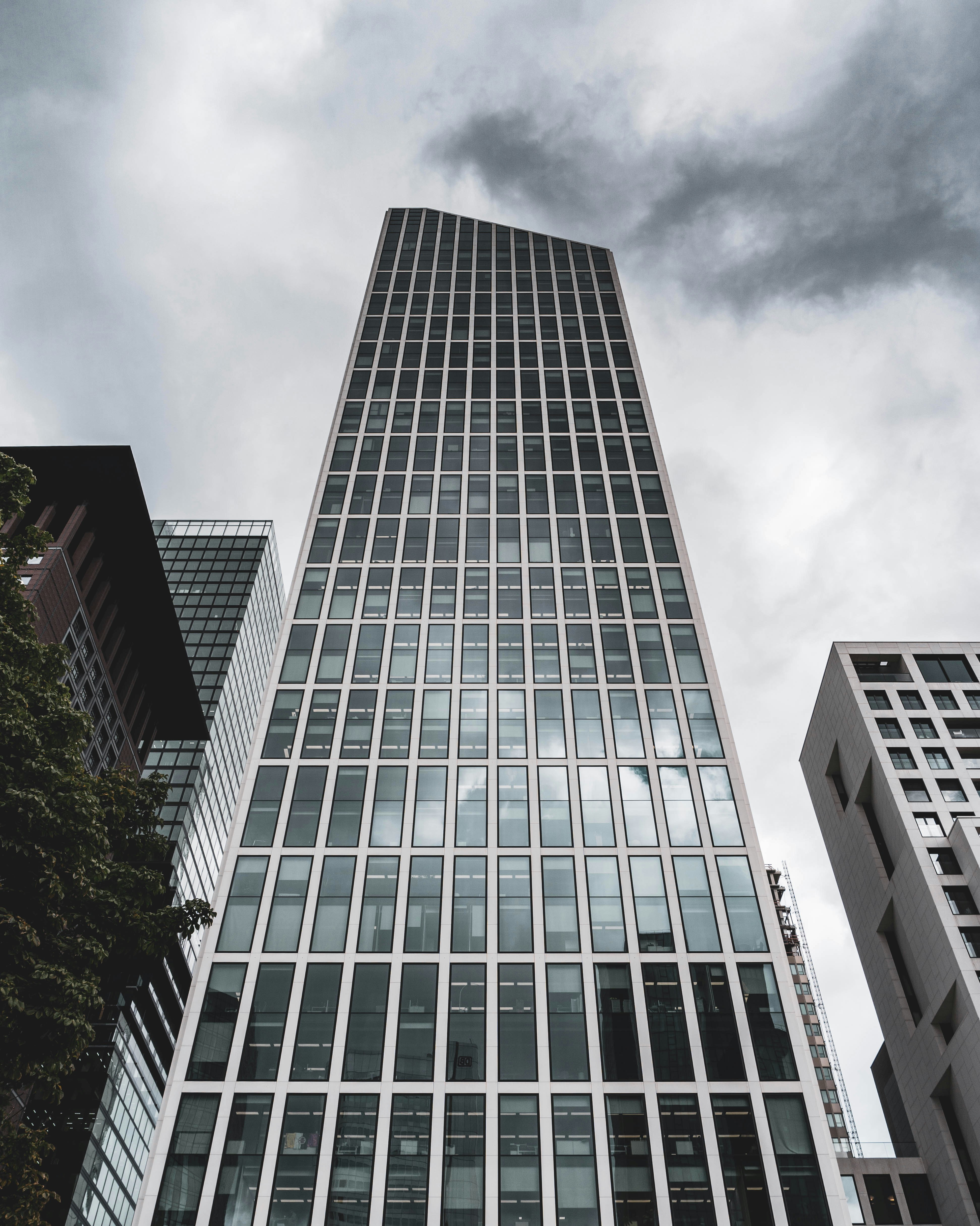 Vertical Grid: The Glass Monolith Reaching into a Stormy Sky