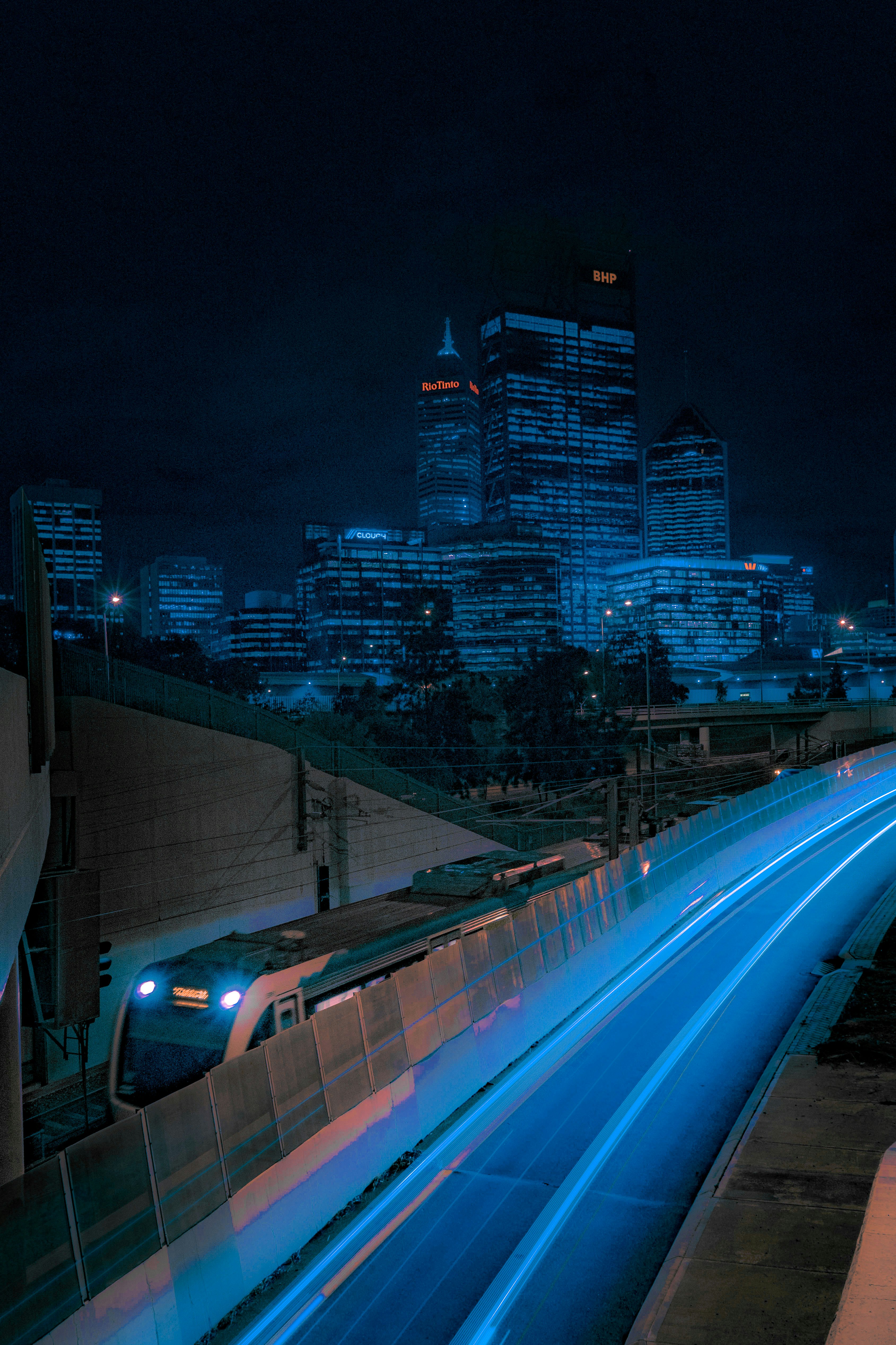 A train glides through a futuristic cityscape illuminated by neon lights, showcasing the dynamic energy of urban life at night.