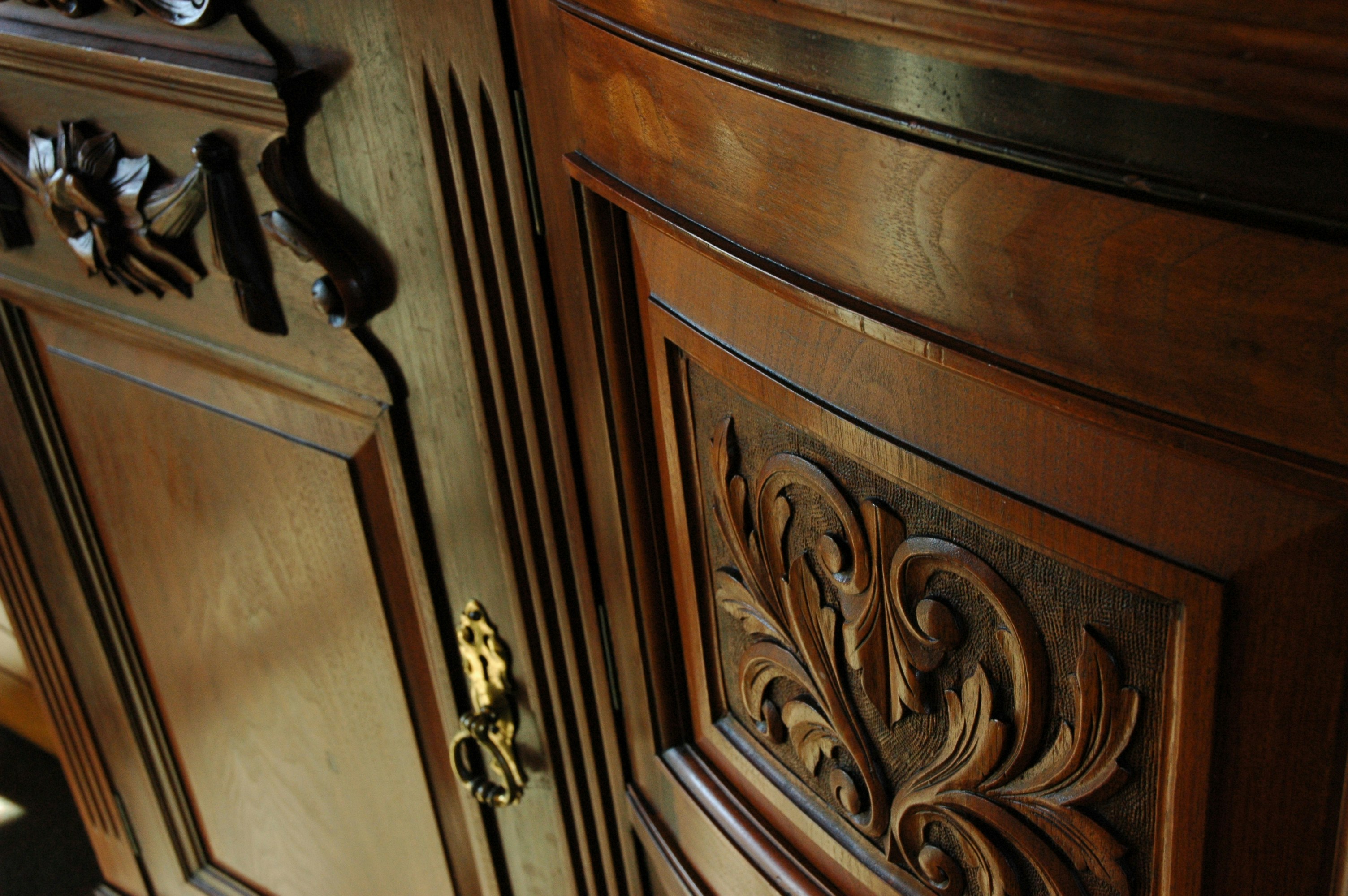 Detailed wooden cabinet featuring ornate carvings and a gleaming brass handle.