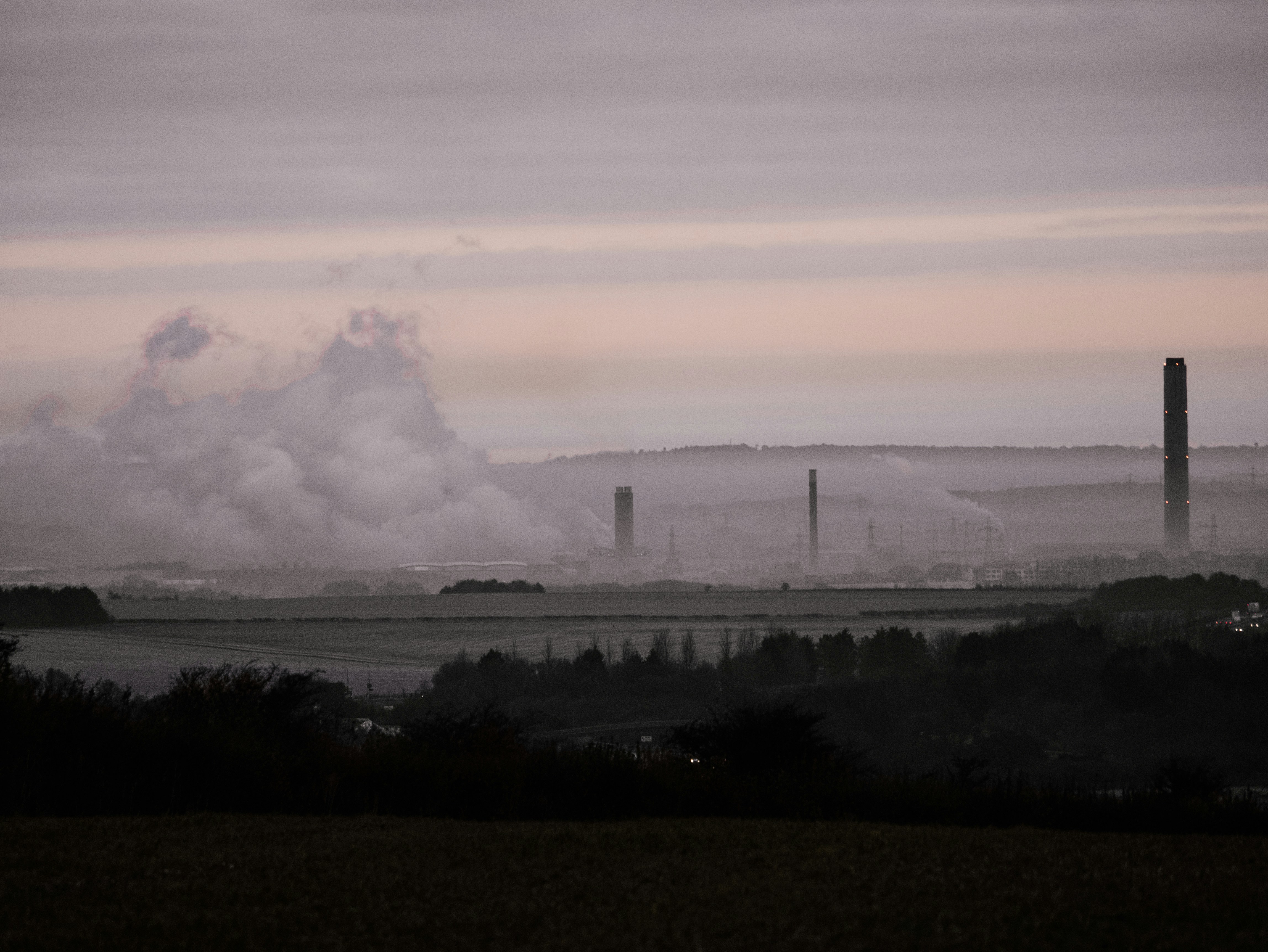 smoke billows from a factory in the distance