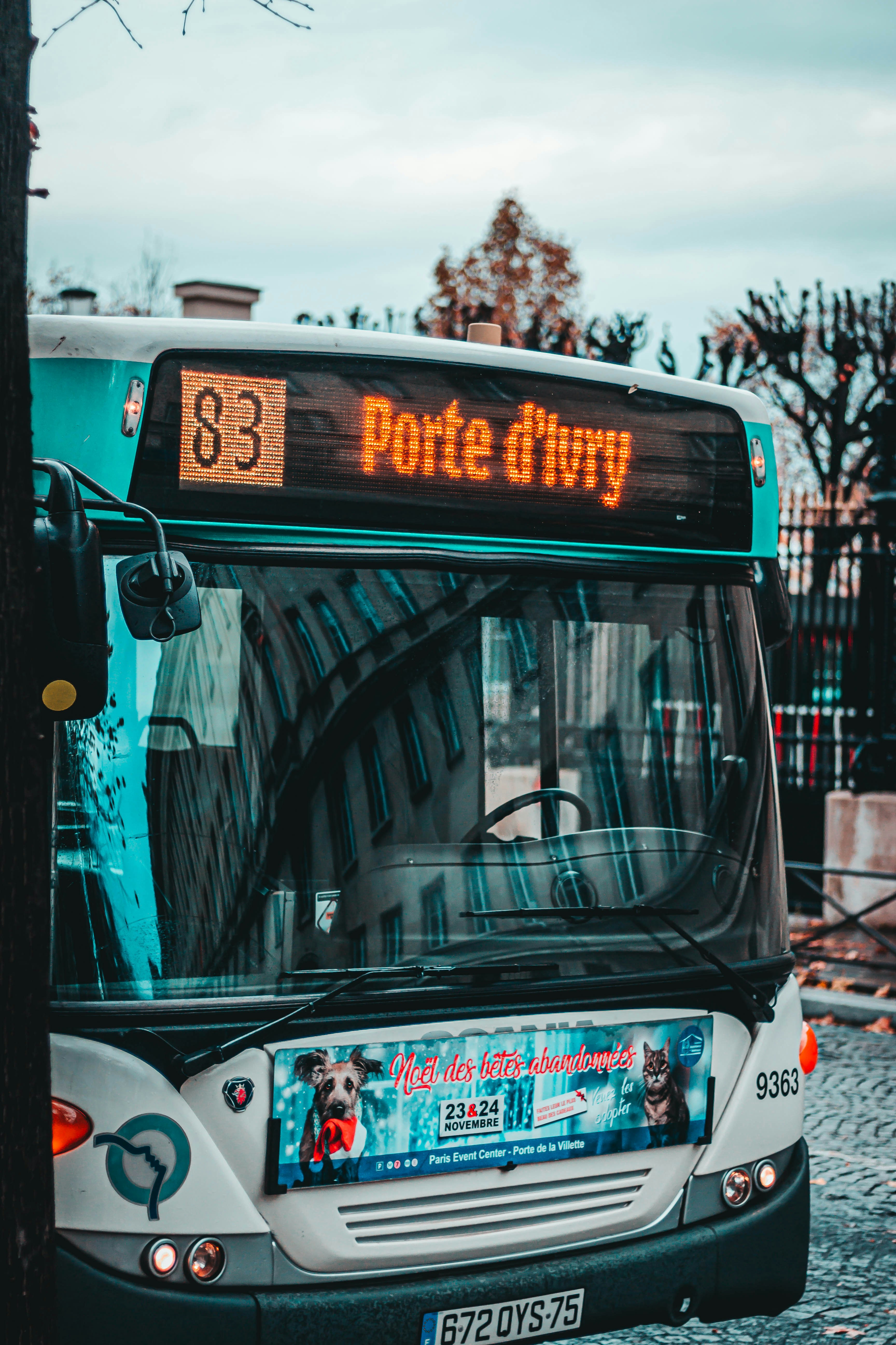 City bus displaying route number 83 and destination 'Porte d'Ivry' amidst a bustling urban backdrop.