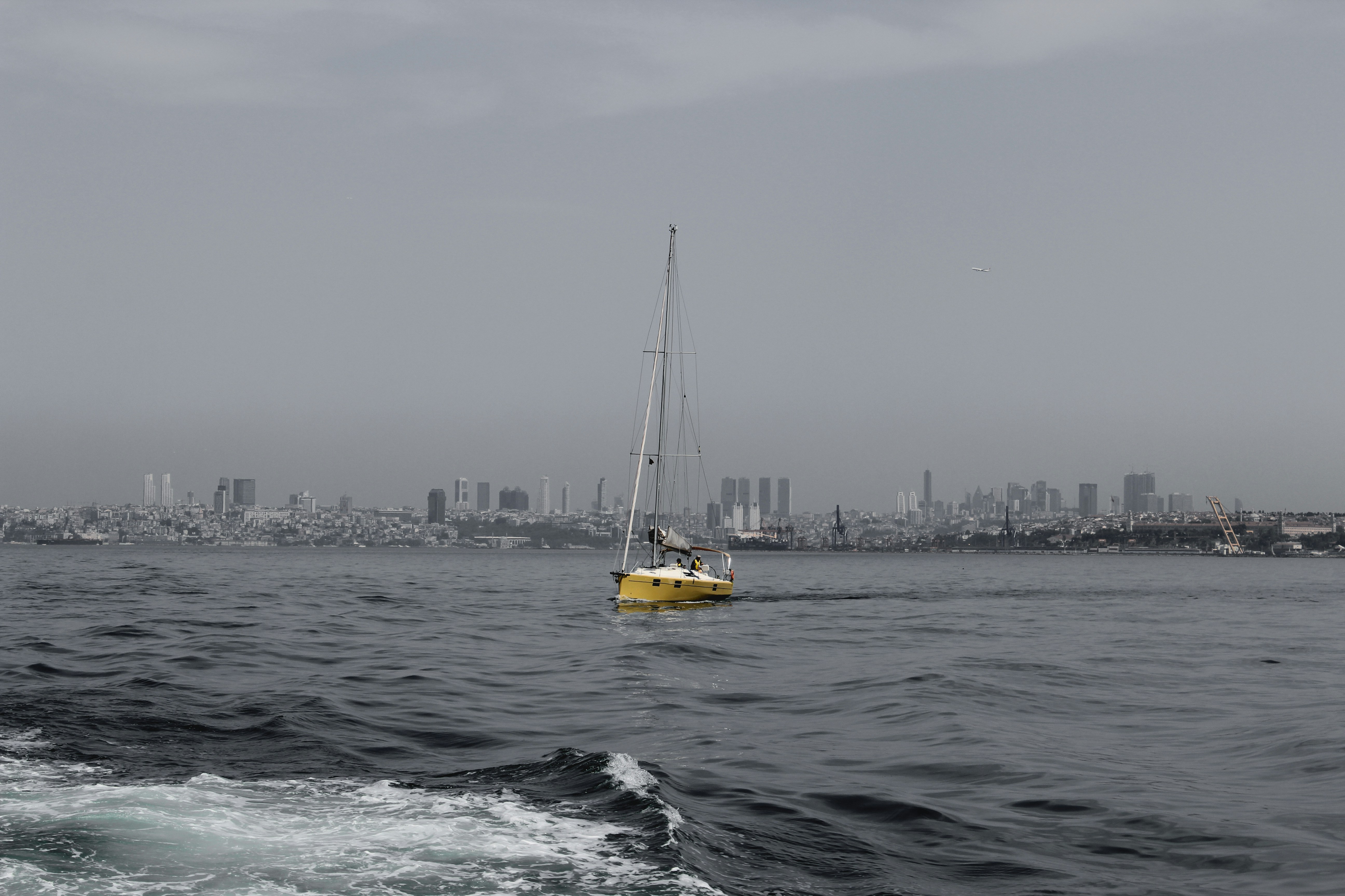 Yellow Sloop on a Quiet Sea Beneath a City Horizon