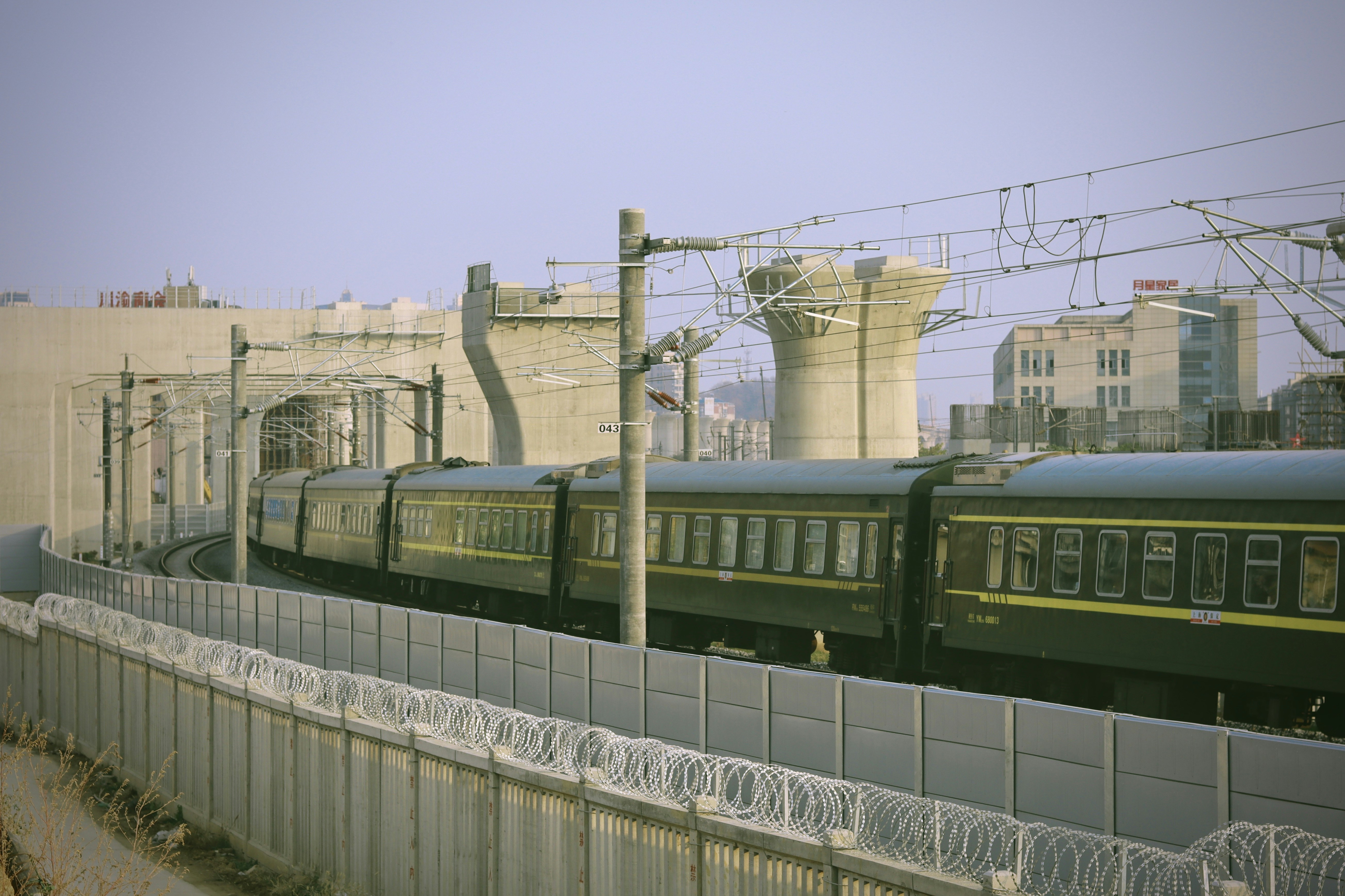 Passenger train passing through Zhenjiang Station with construction of new railway in the background.