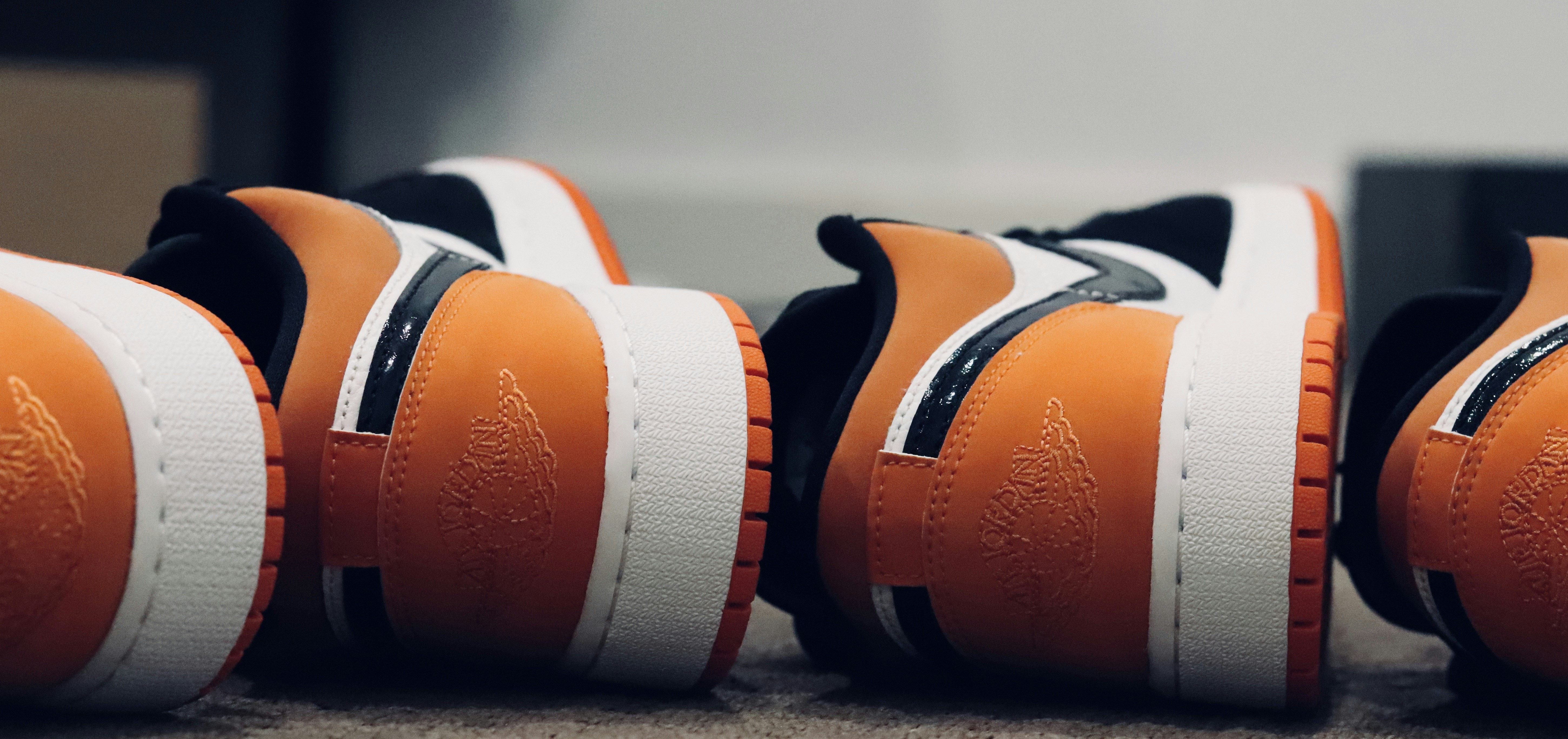 Row of Orange-Accent Sneakers Resting on a Carpeted Floor
