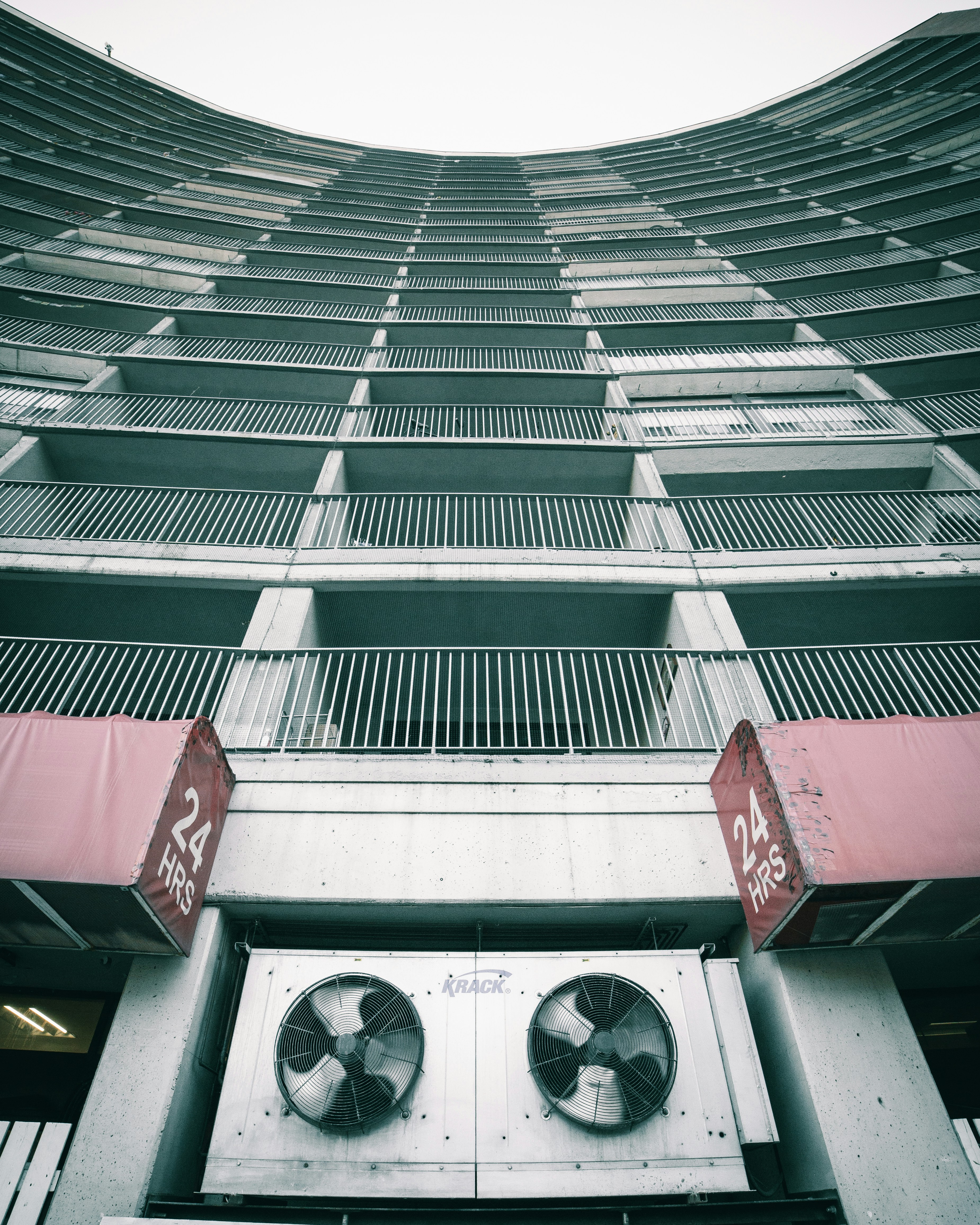View of a multi-story parking structure with visible air conditioning units and balconies, emphasizing architectural lines and urban design.