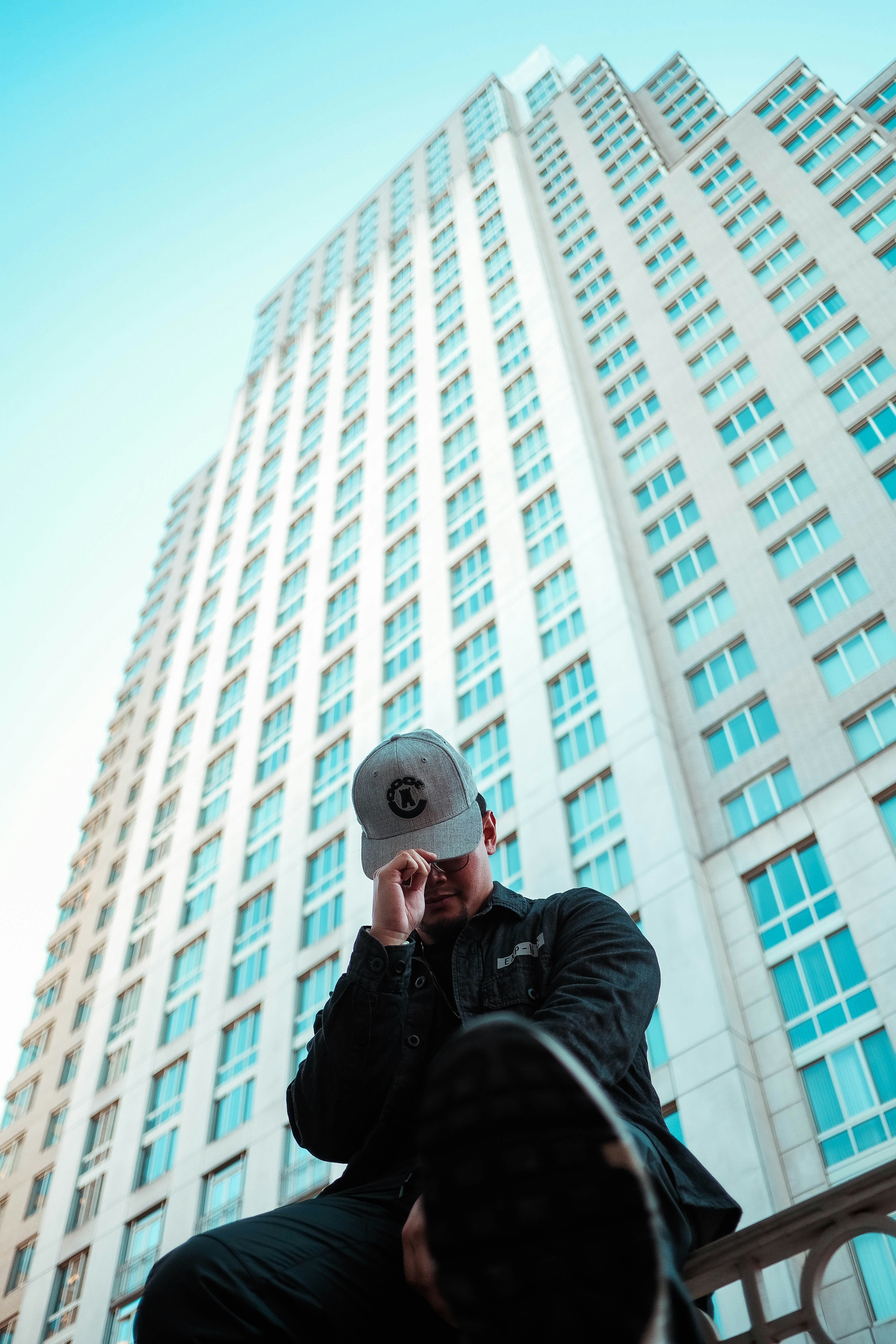Woman sitting on metal fence overlooking building photo – Free Blue ...