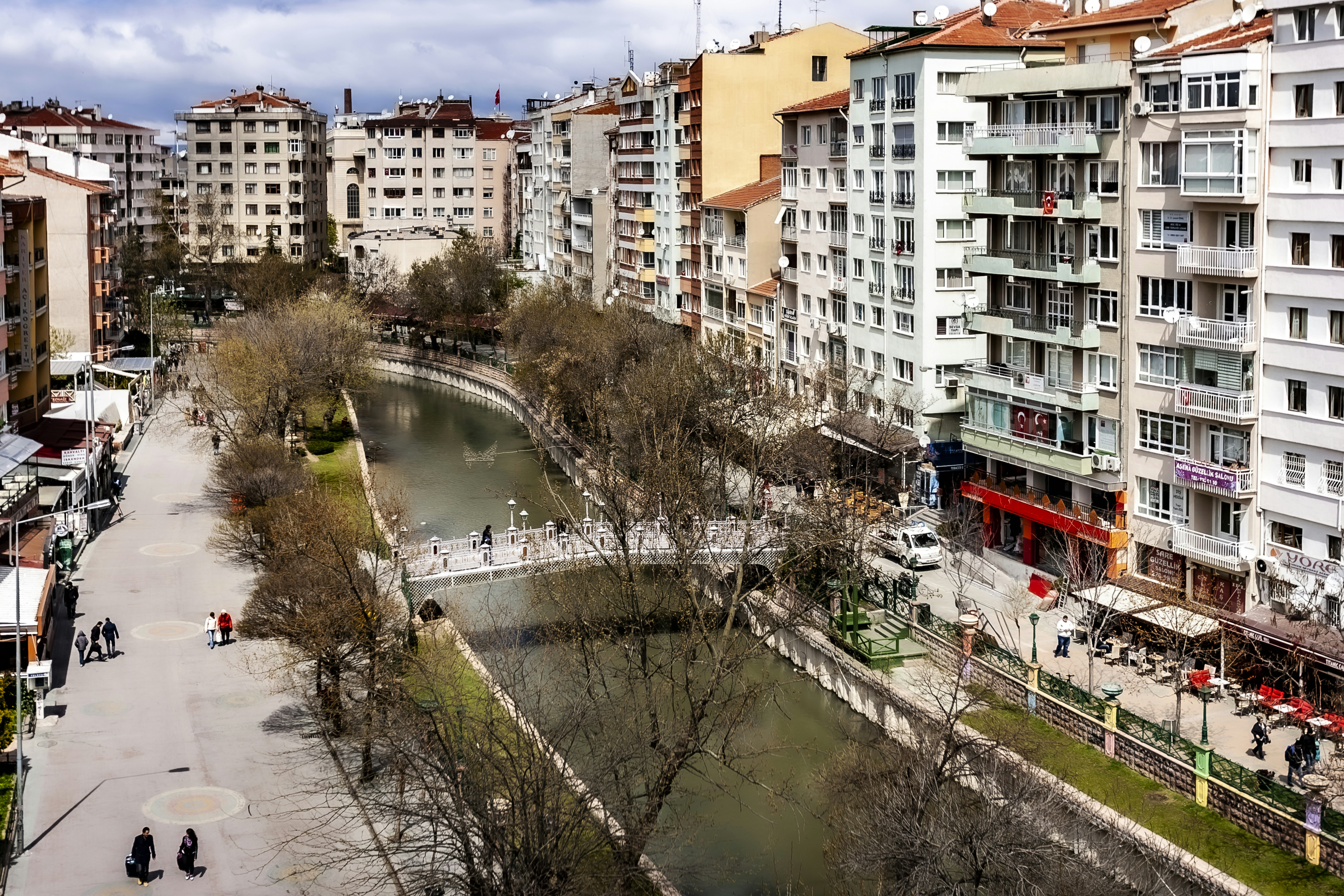 Aerial view of Porsuk River flanked by residential buildings and a tree-lined promenade.