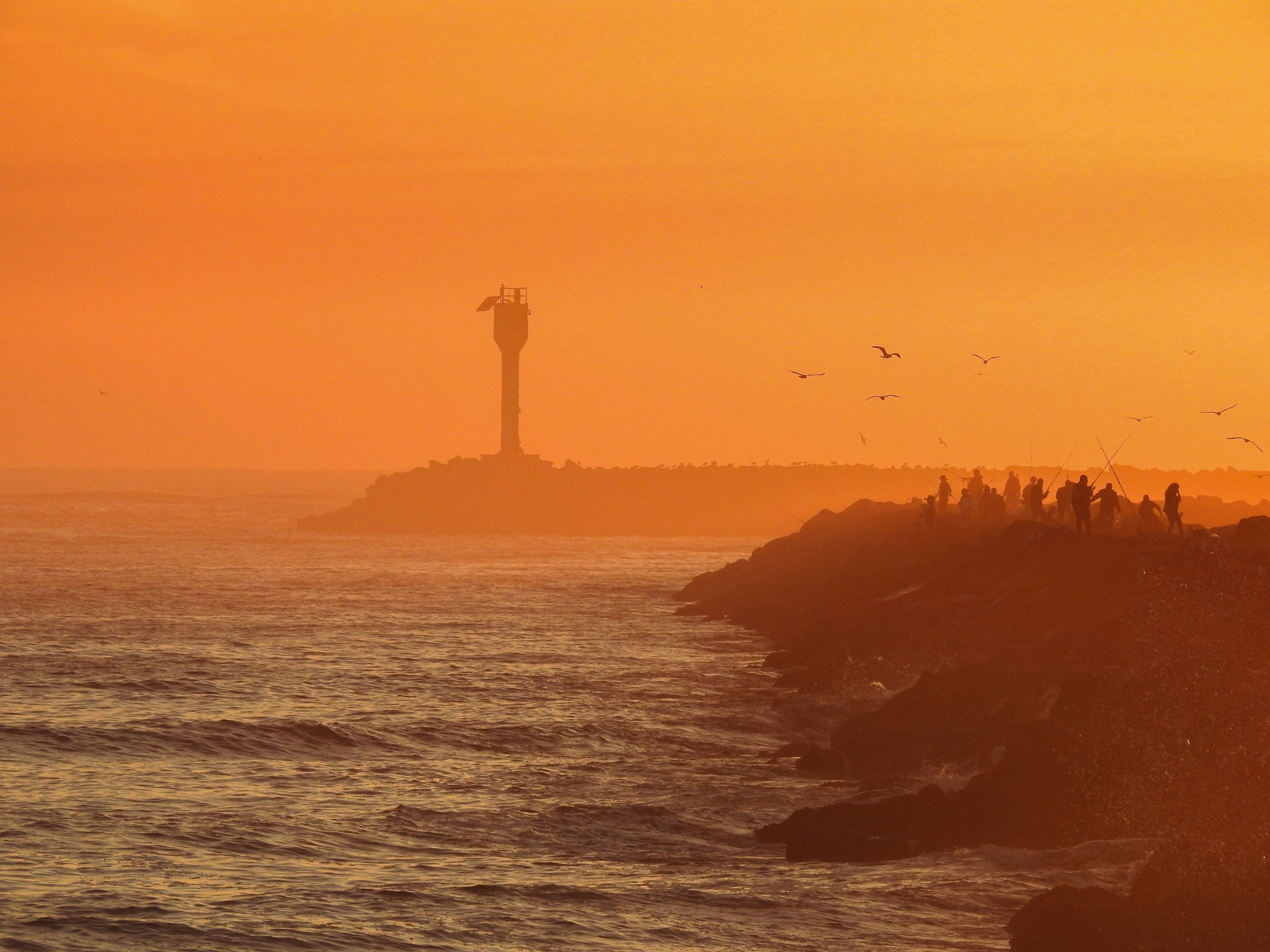People standing on rocks at sunset.