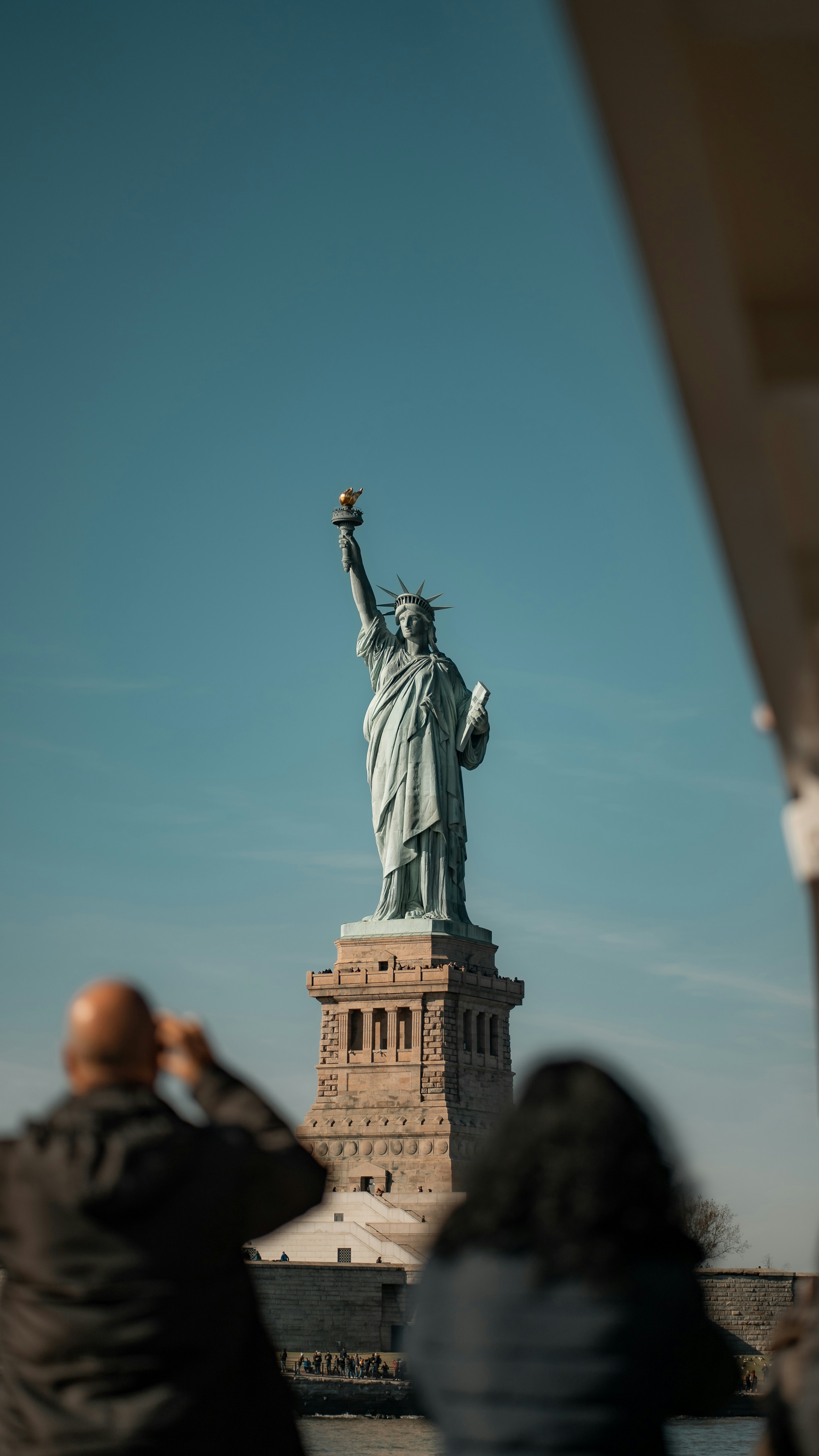 a group of people standing in front of the statue of liberty