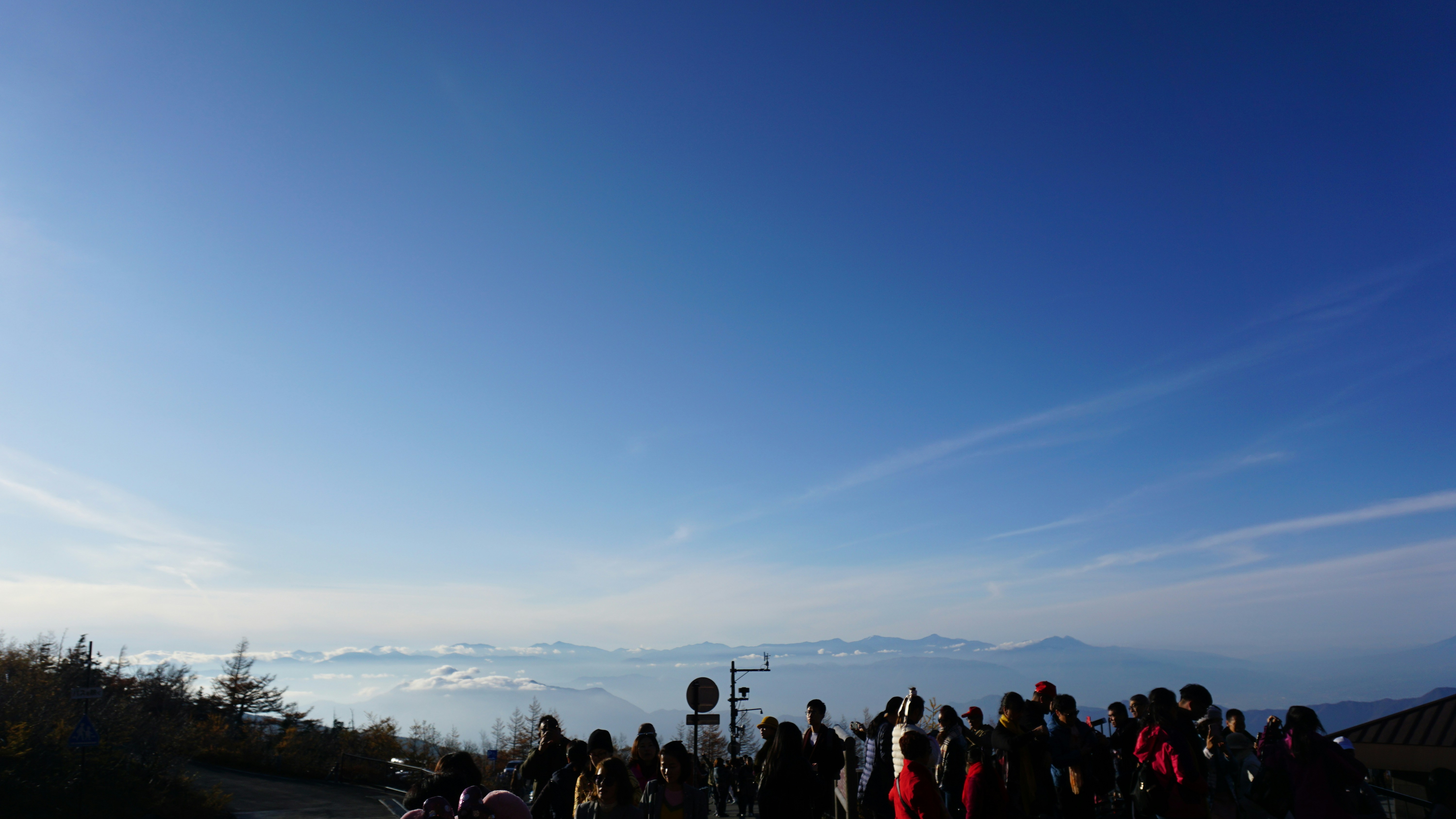 Silhouetted group of people gathered under a clear blue sky with distant mountains.