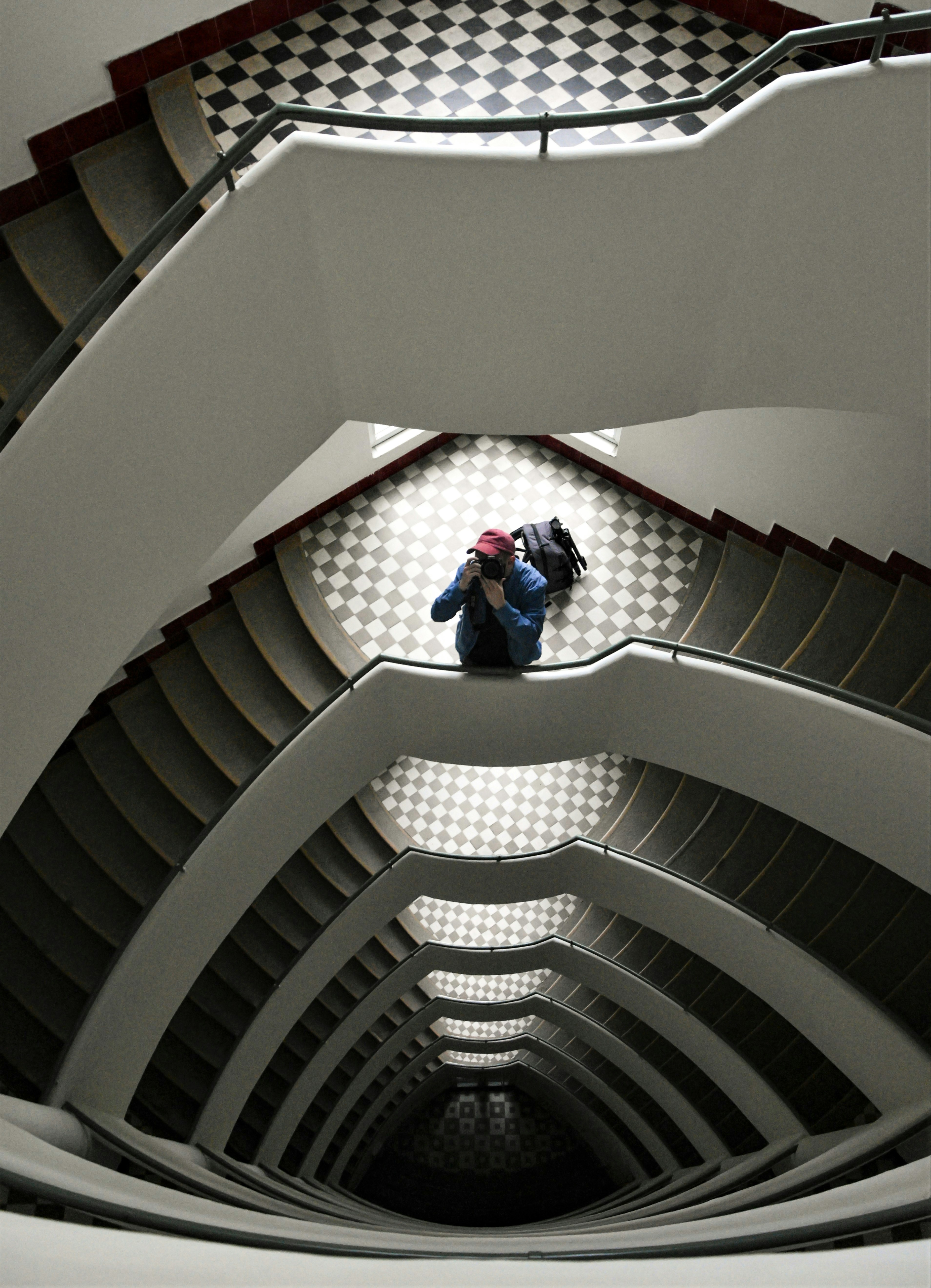 High-angle photo of man standing in front of balustrade of staircase ...