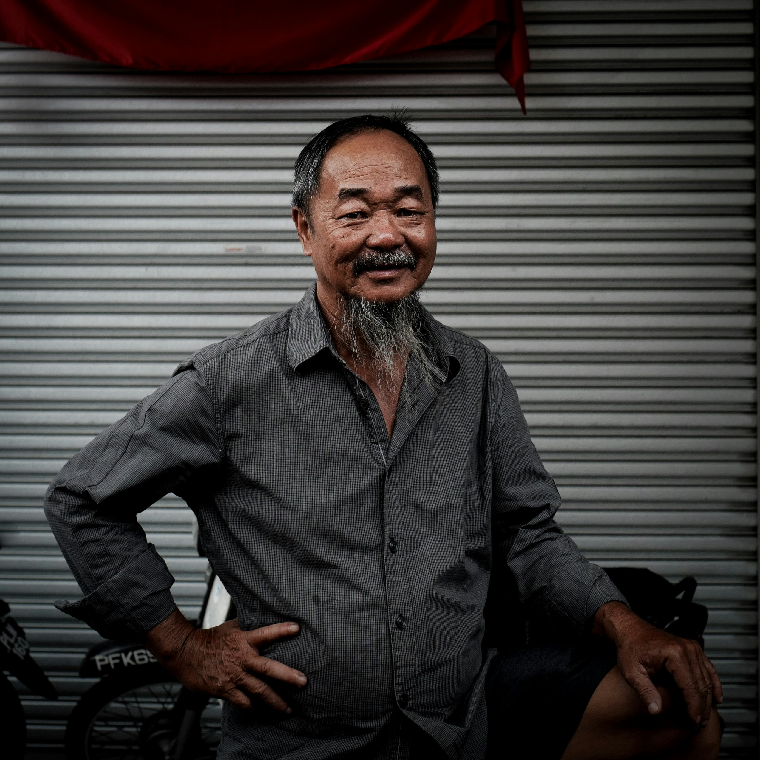 Man in front of corrugated shutter: quiet confidence under shadowed light