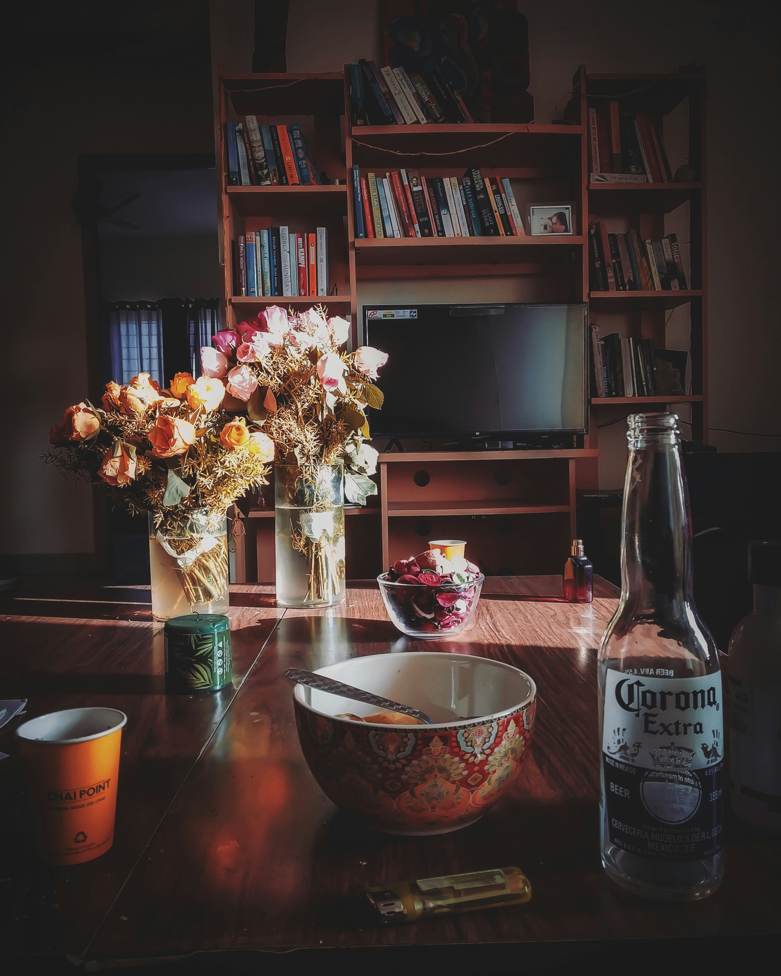 Warm Still-Life at Dusk: Dried Roses, a Corona Bottle, and a Tabletop Glow