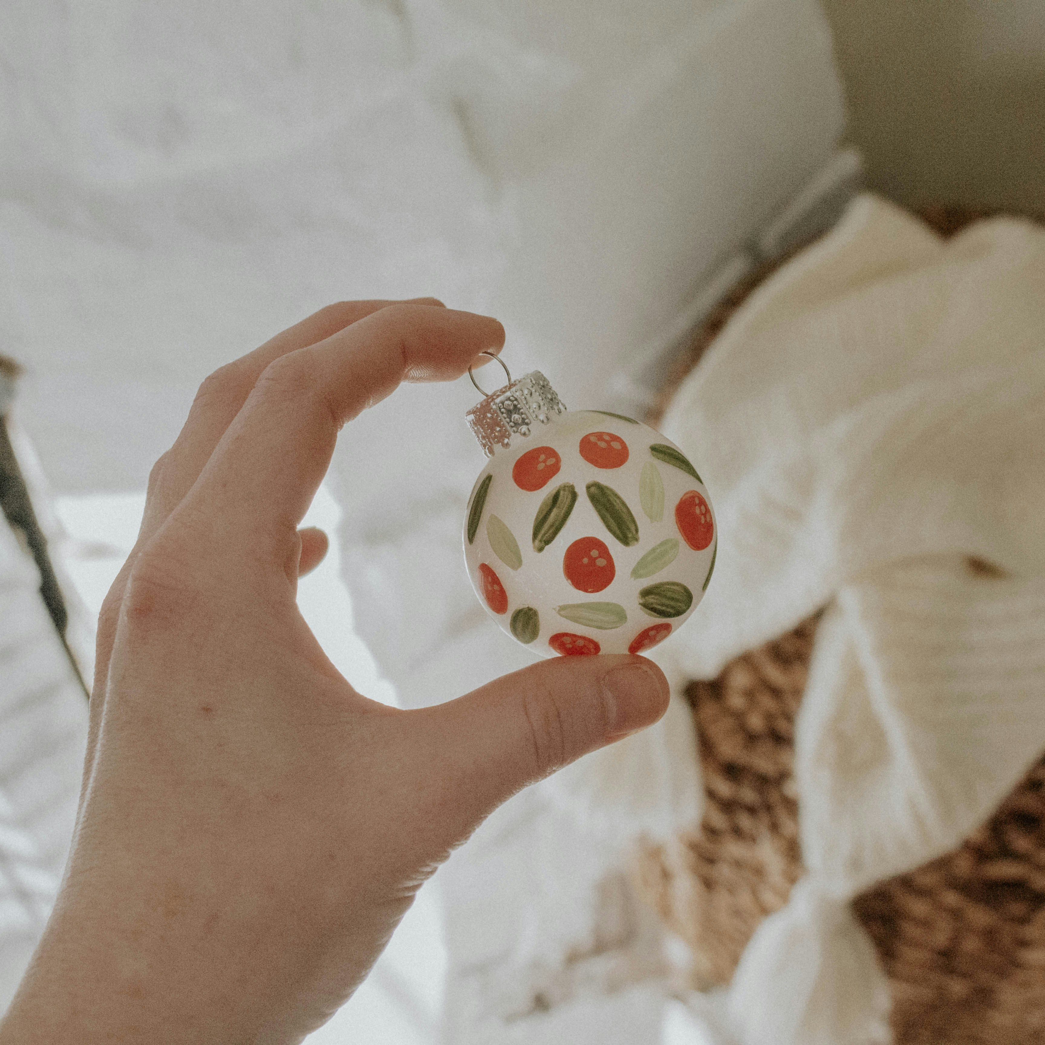 Tiny Berry-Patterned Ornament Gripped Against a Cozy Textile Backdrop