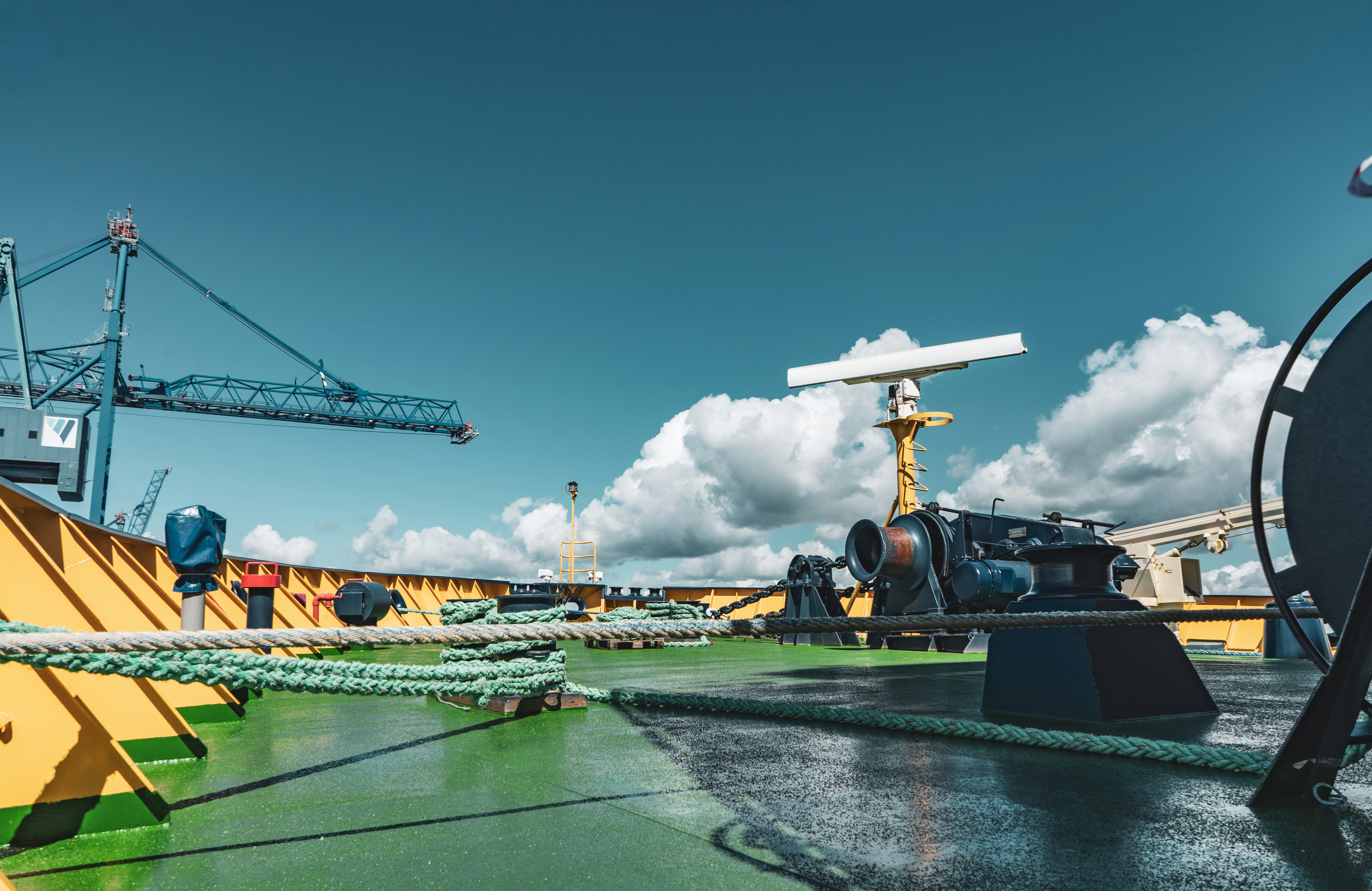 Ship deck with industrial equipment and cranes under a vibrant sky.