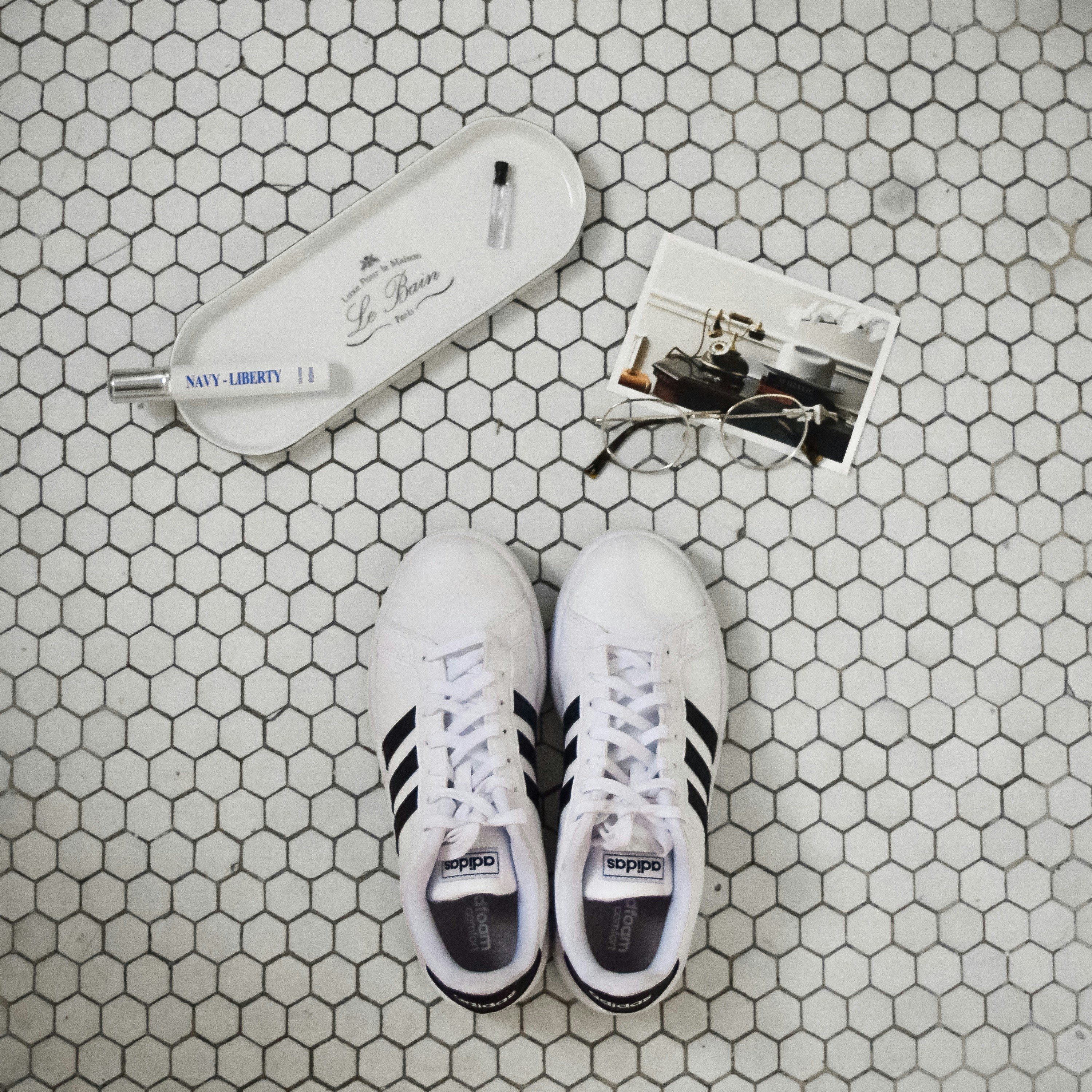 Hex Tile Still-Life: White Adidas Pair Anchored by a Spare Case and Polaroid